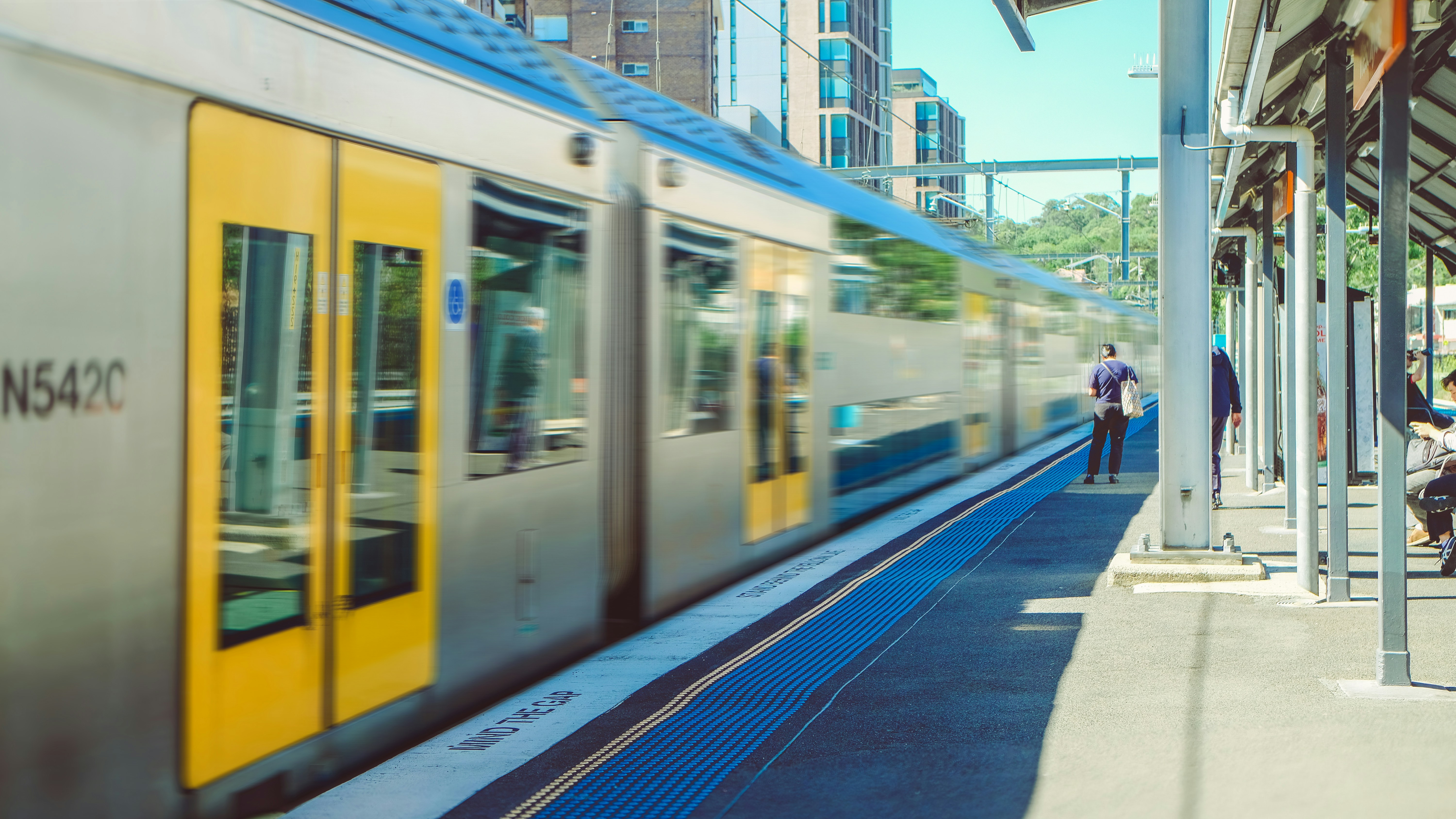 Platform Gaze: A Yellow-Fronted Train Pausing at a Modern Station