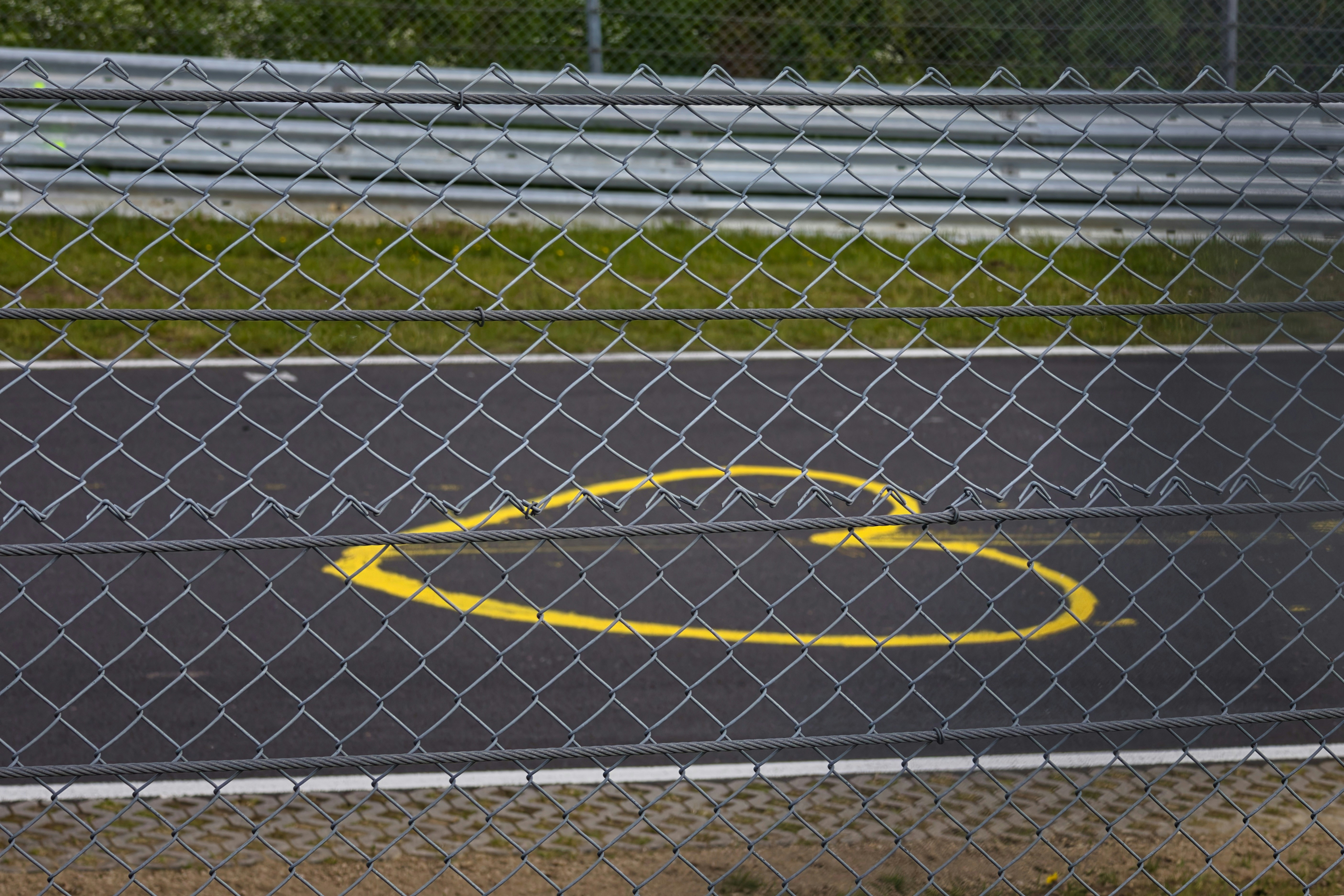Yellow chalked spiral on a chain-link barrier