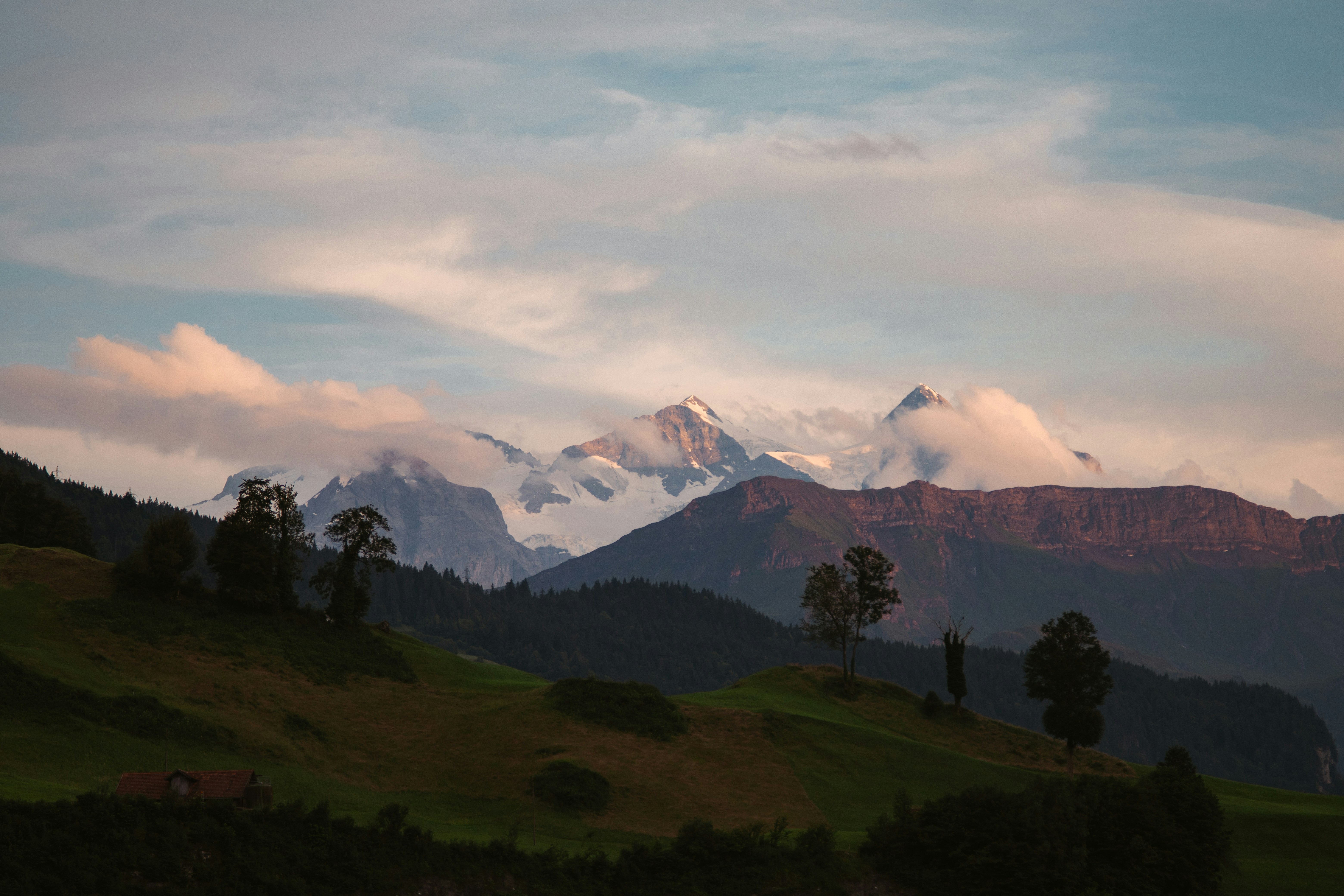 Snow-capped Peaks Emerging from Gentle Hills at Dusk