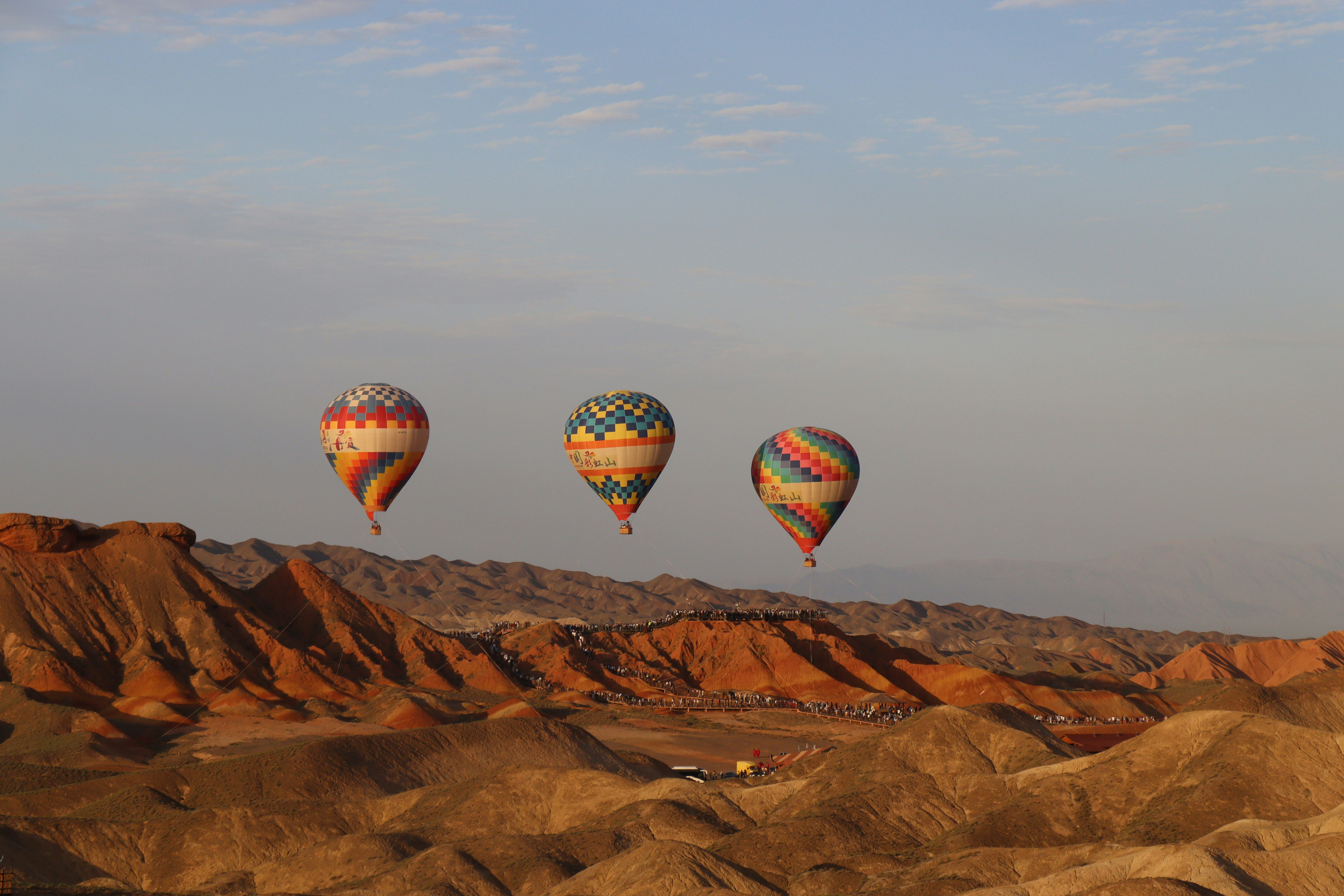 Three Colorful Balloons Over Arid Dunes at Dusk