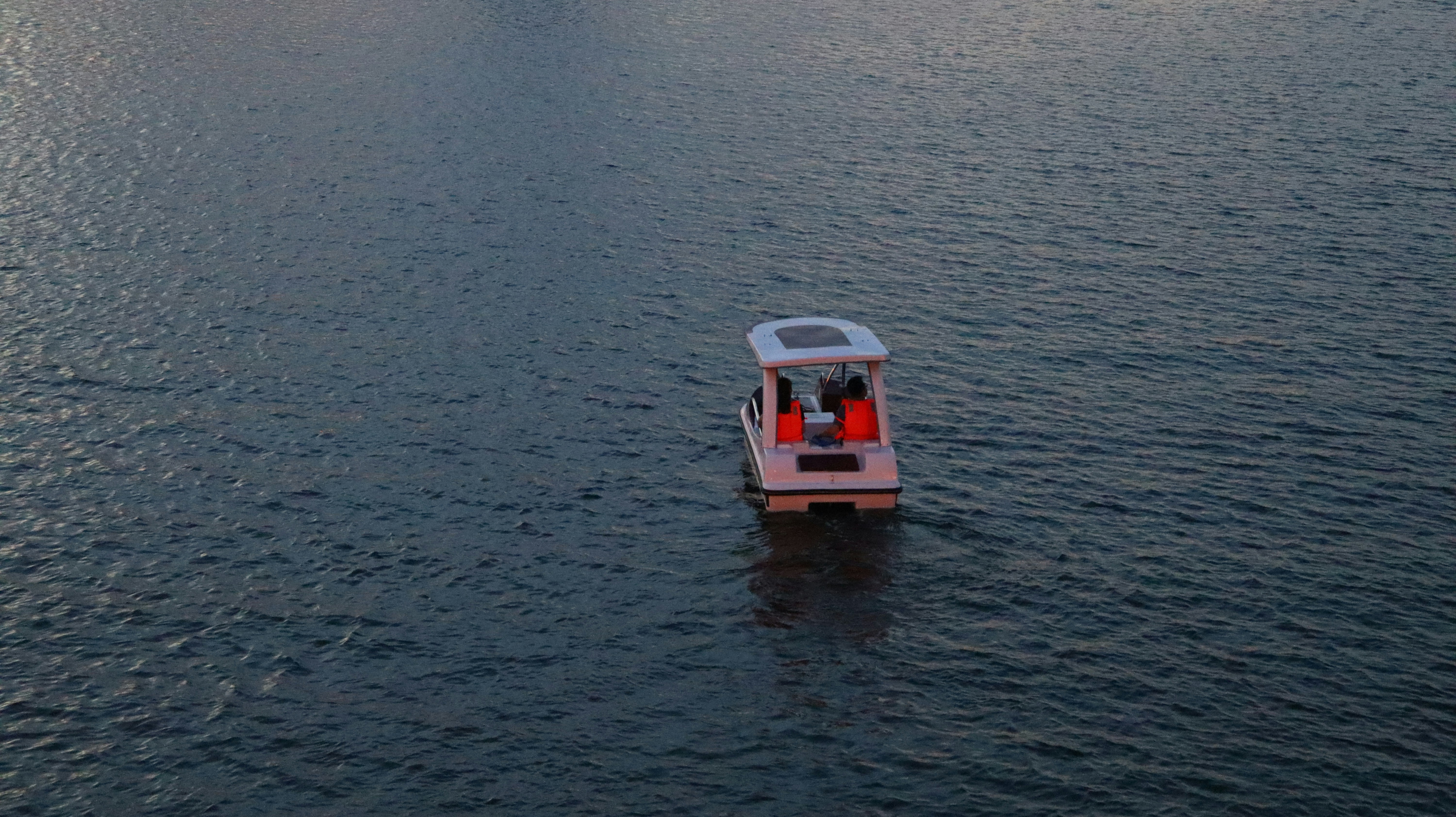 Red-Water Escape: A lone boat glides through a calm blue sea