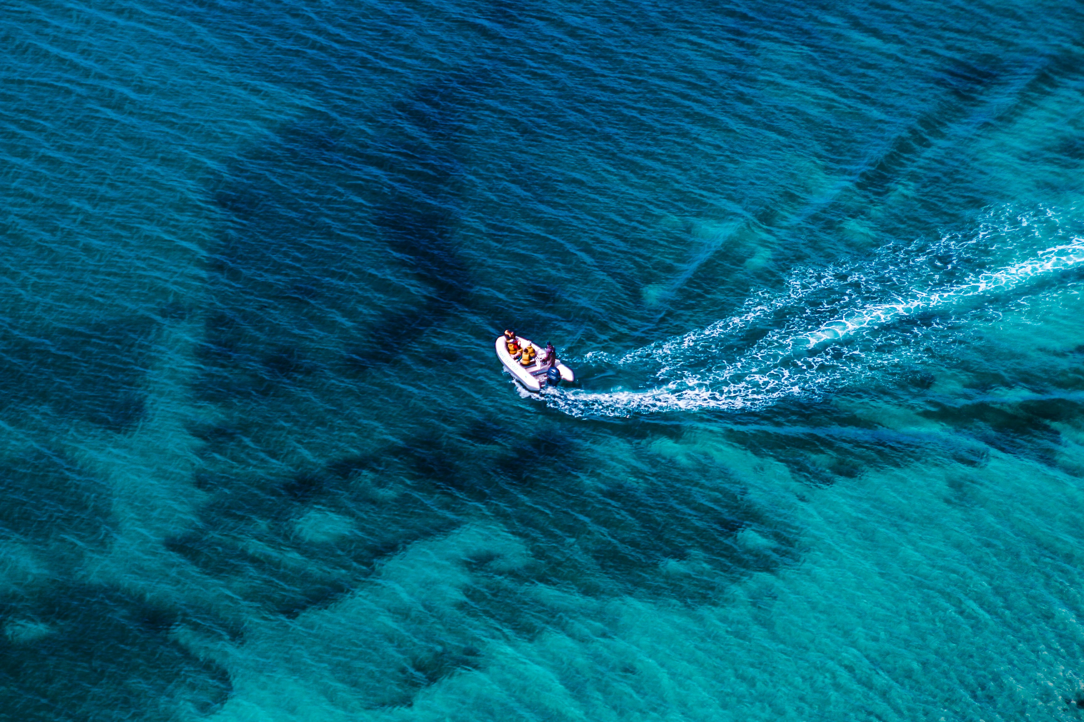A lone speedboat carves a turquoise wake through tropical seas