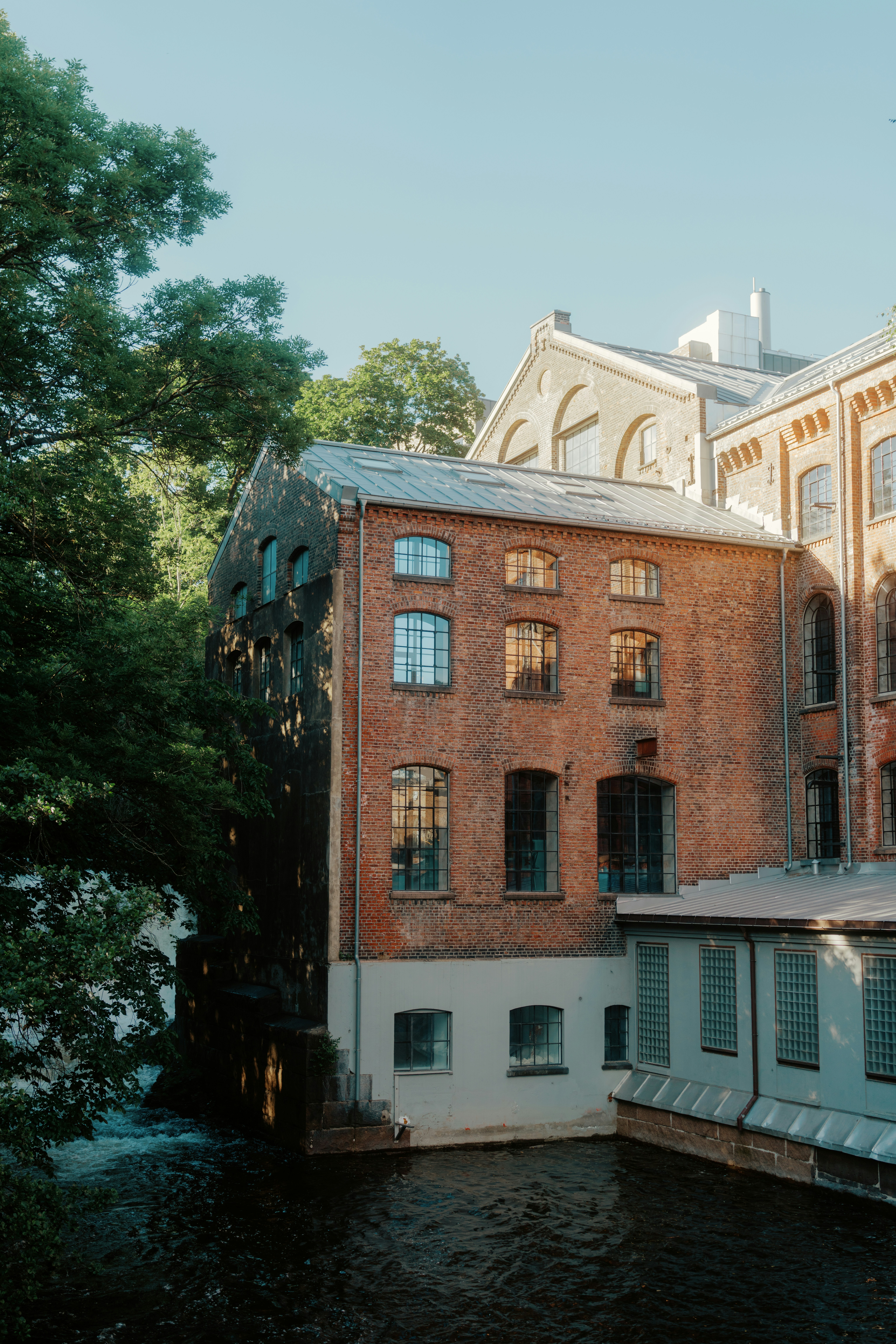 Brick Factory by the Waterfall: Sunlit Facades and Quiet Channel