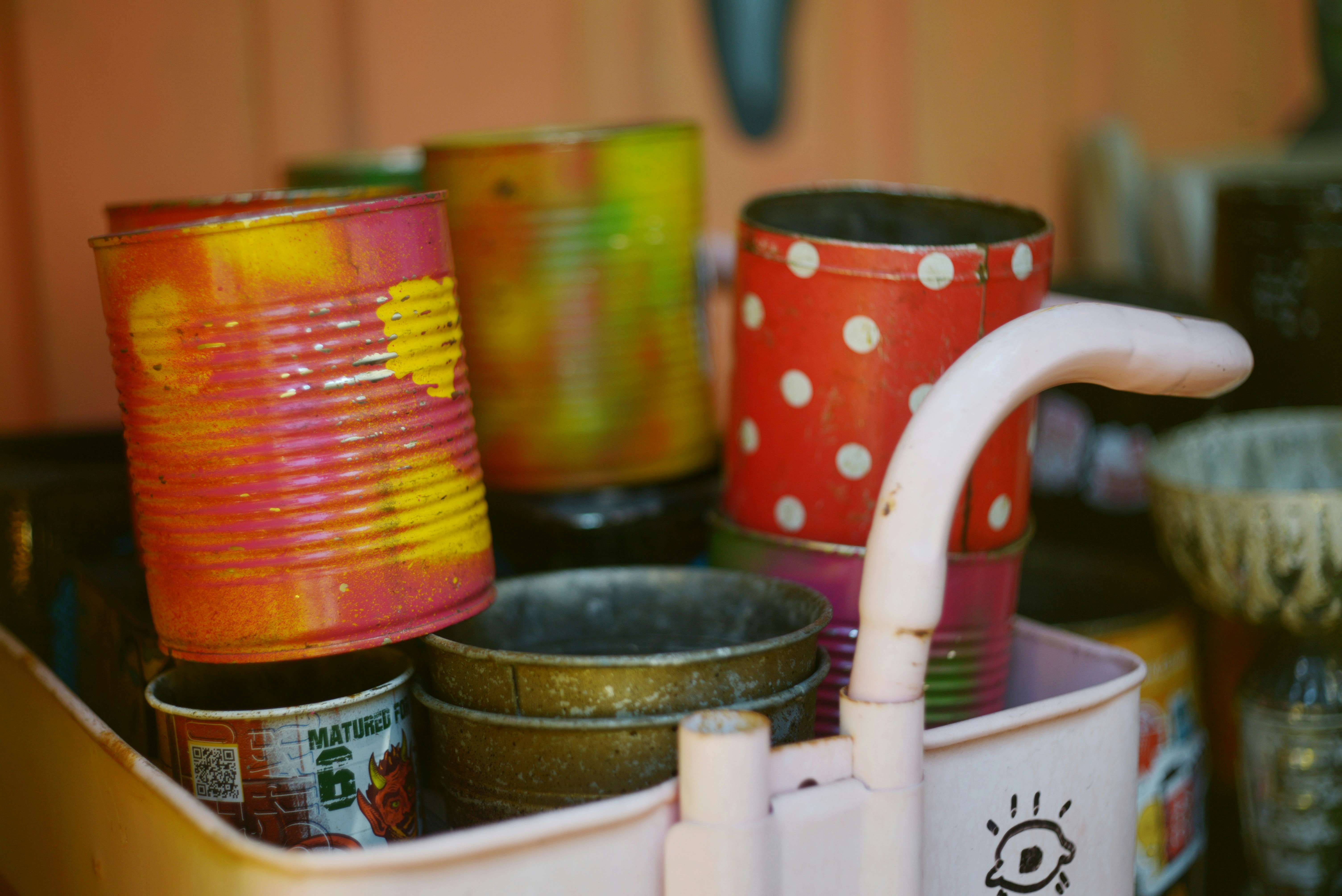 Stacked colorful decorated tin cans and craft supplies.