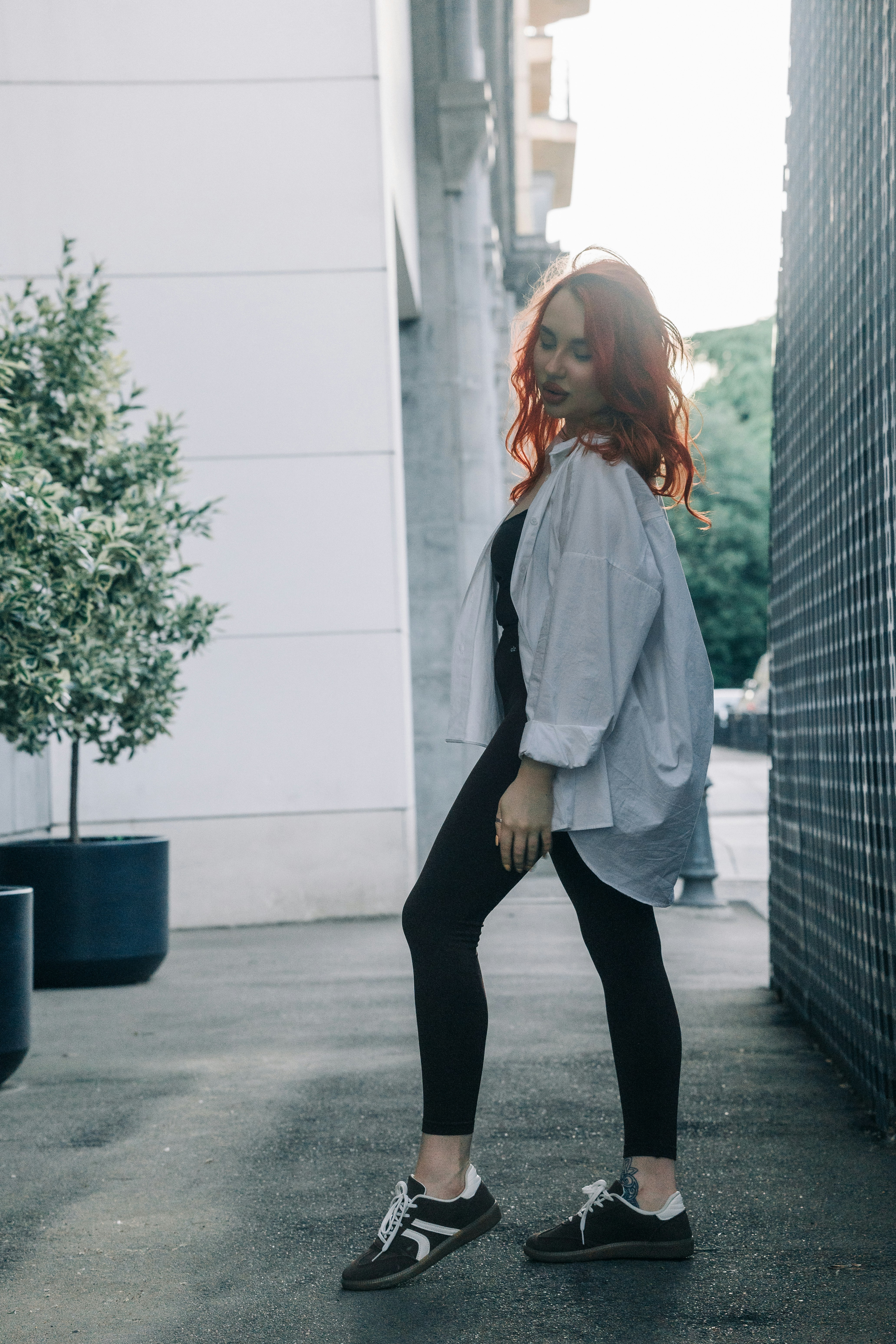 Urban Stride: A Woman in a Loosened Shirt Walks the Narrow Alley