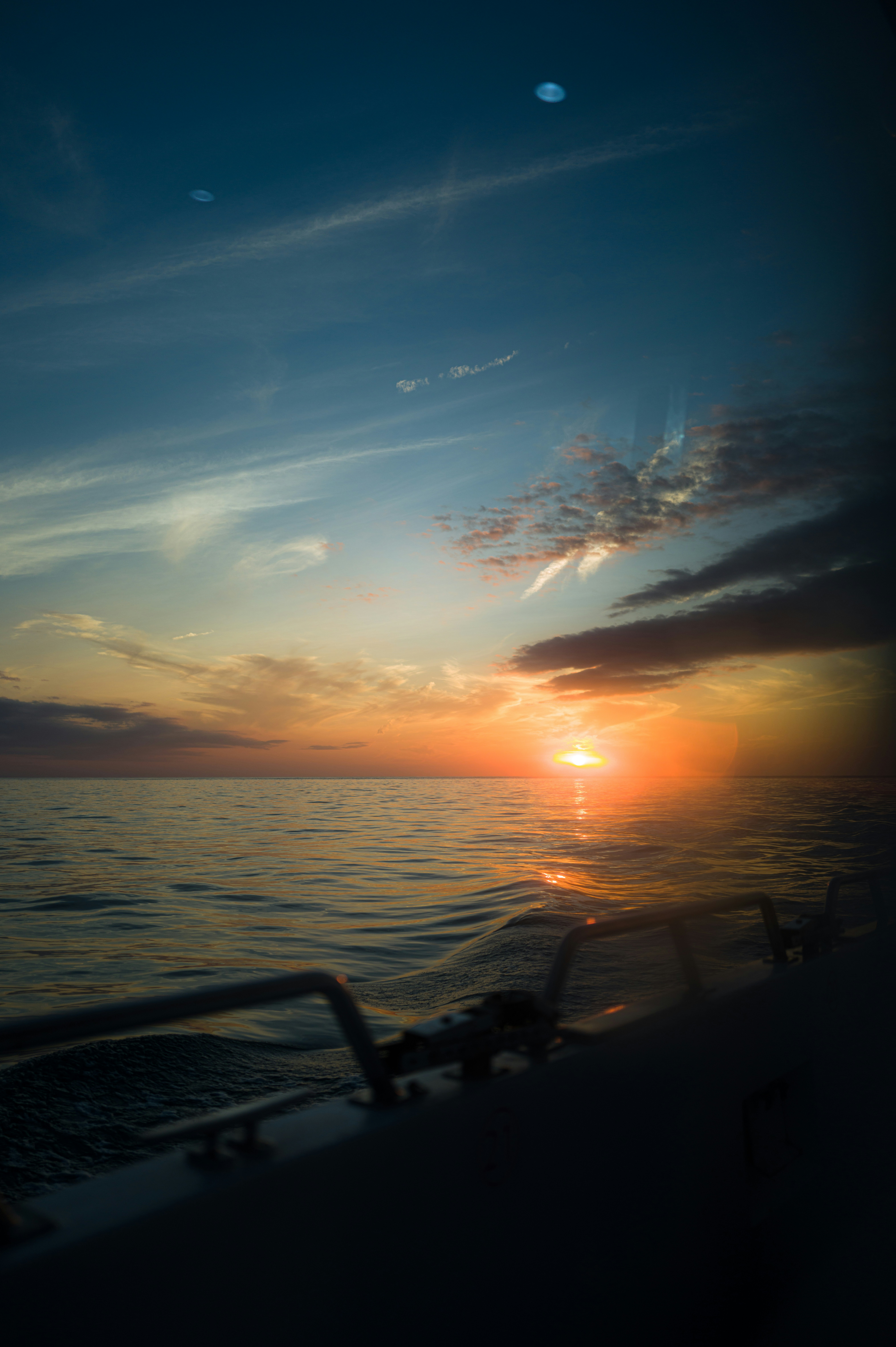 Sunlit Horizon: Sunset Over Calm Seas from a Boat Deck