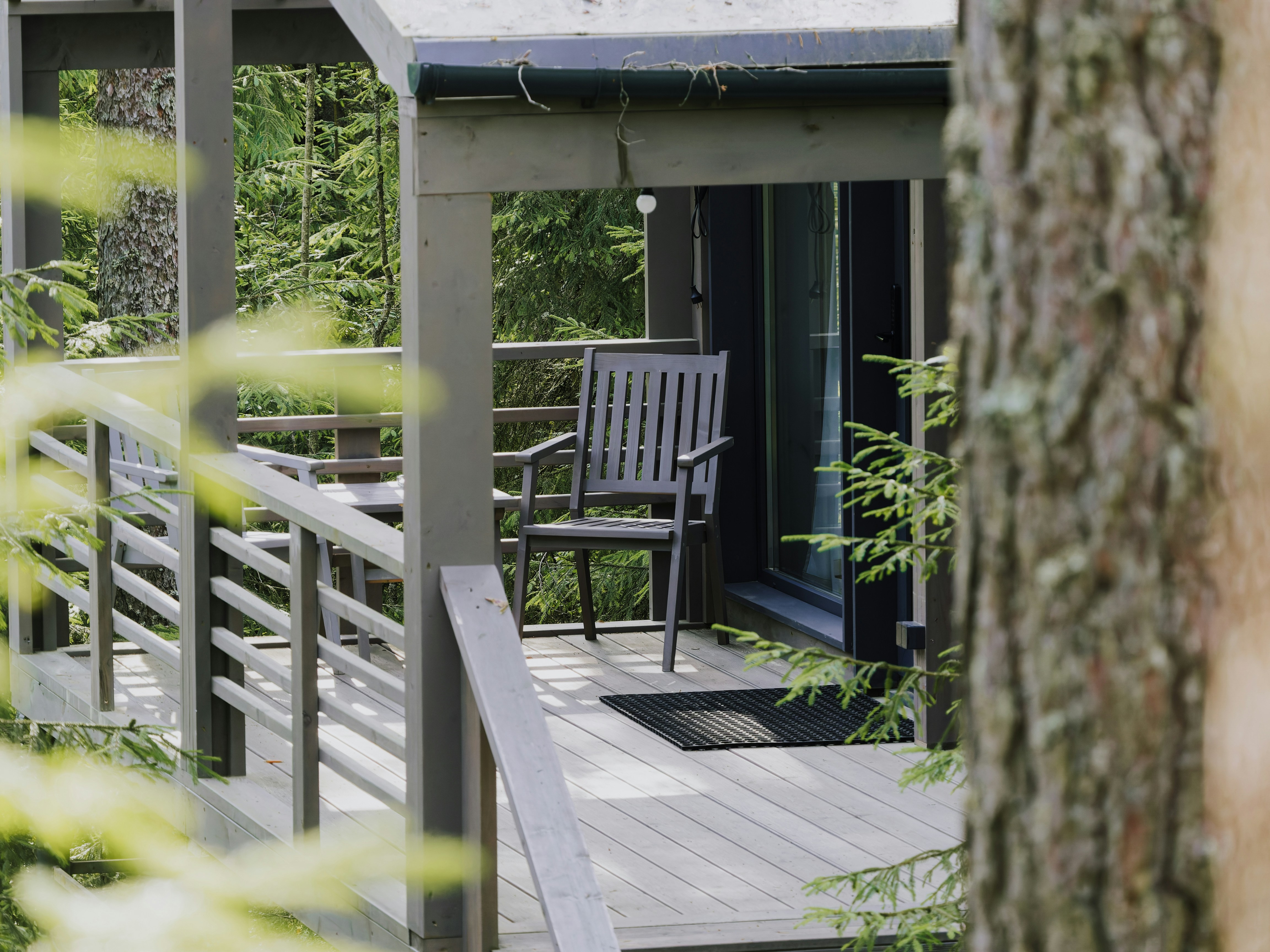 Wooden porch at a forest cabin with a lone chair