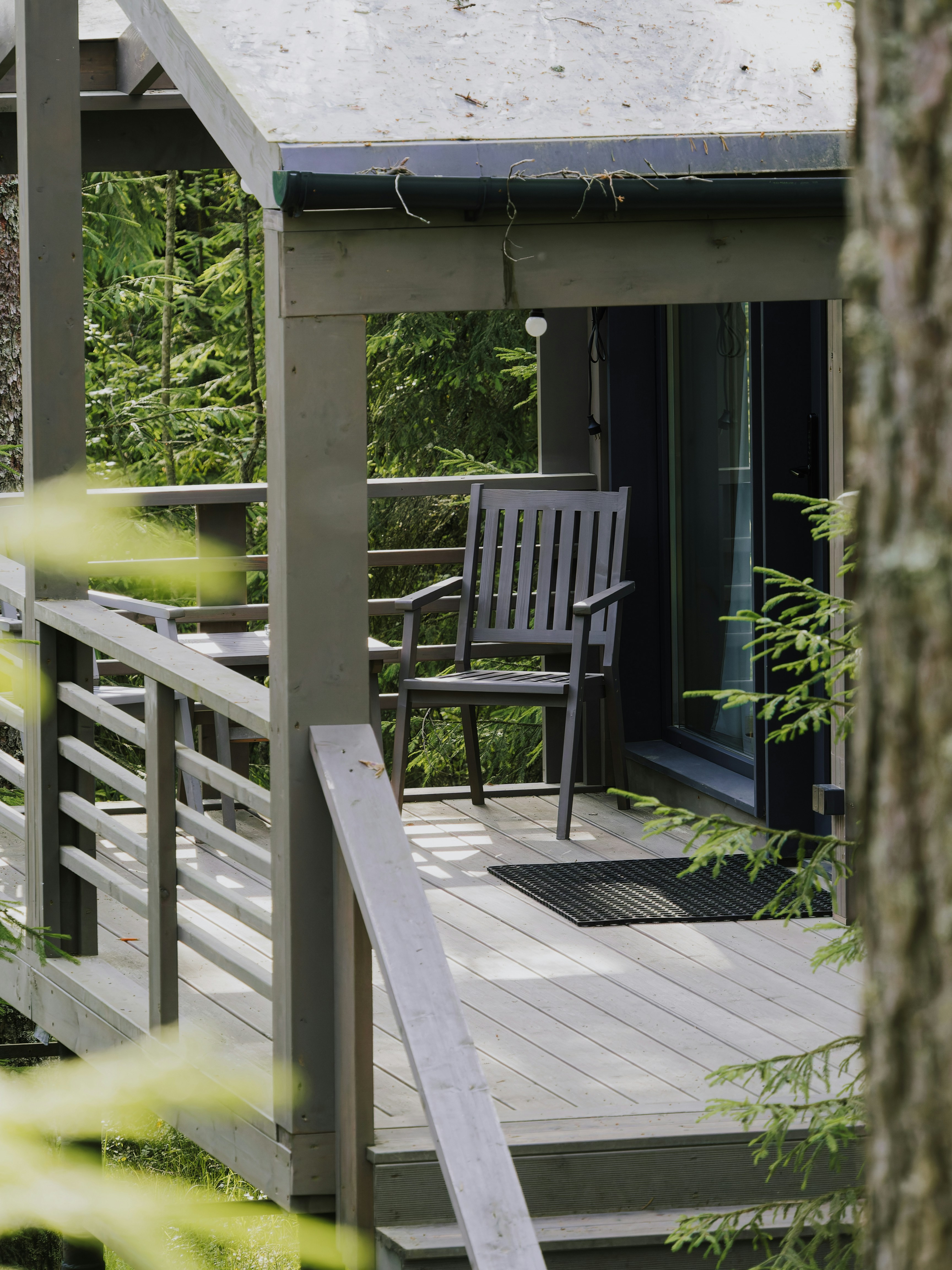 Wooden deck chair on a forest‑framed cabin porch