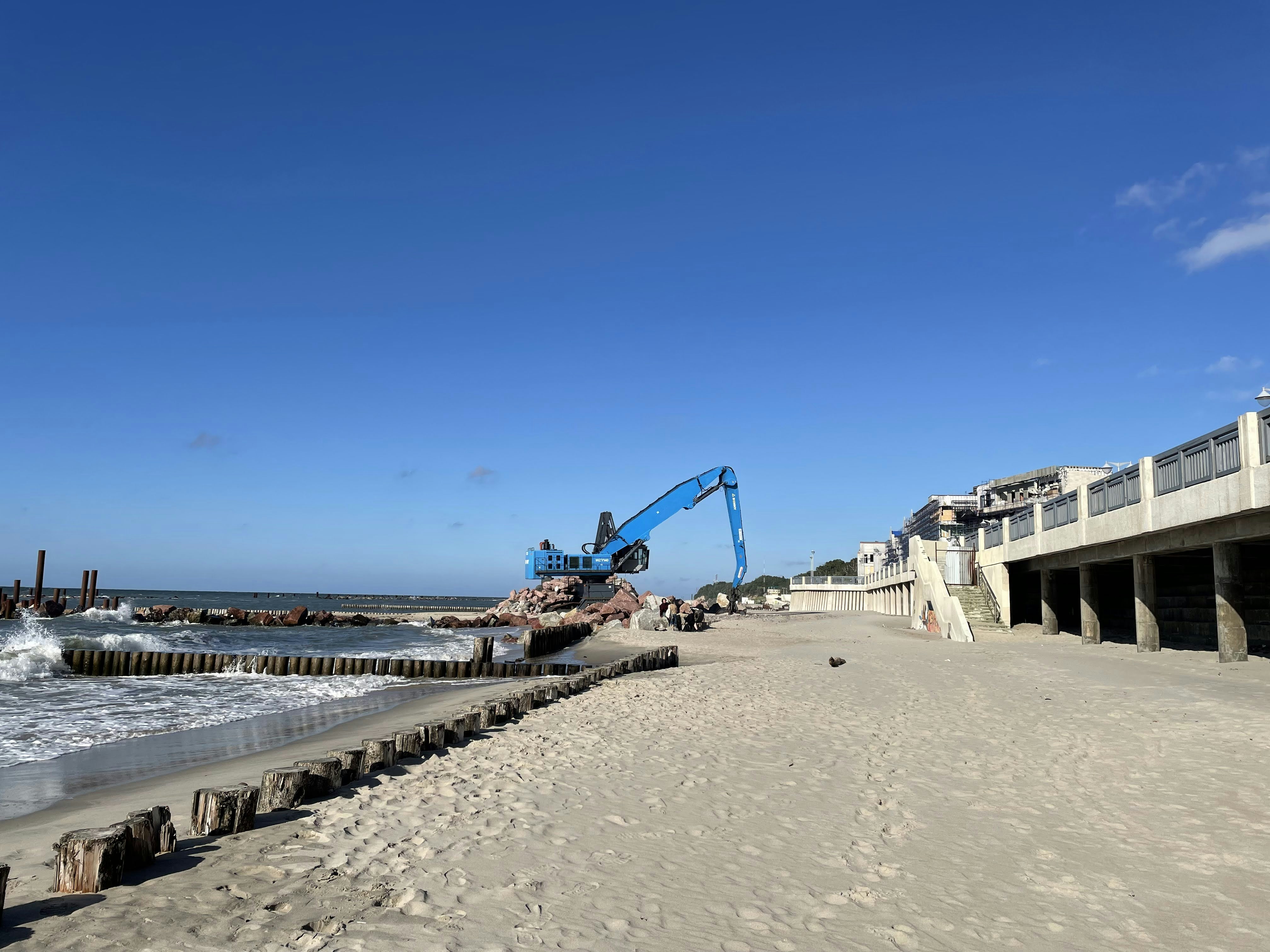 Blue excavator at the quiet seaside construction zone