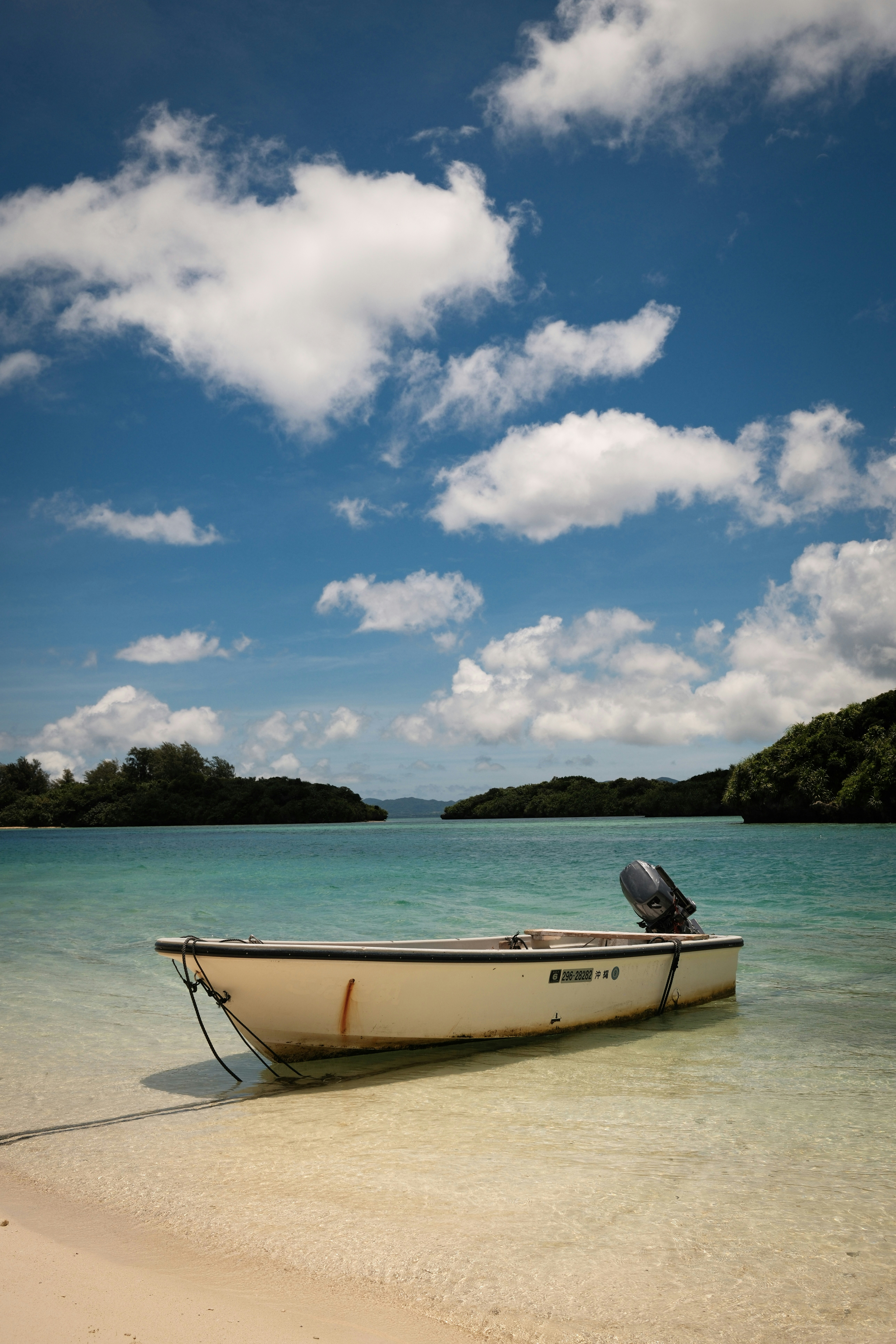 Lone Boat Resting on Tropical Shore Beneath a Cloud-dotted Sky