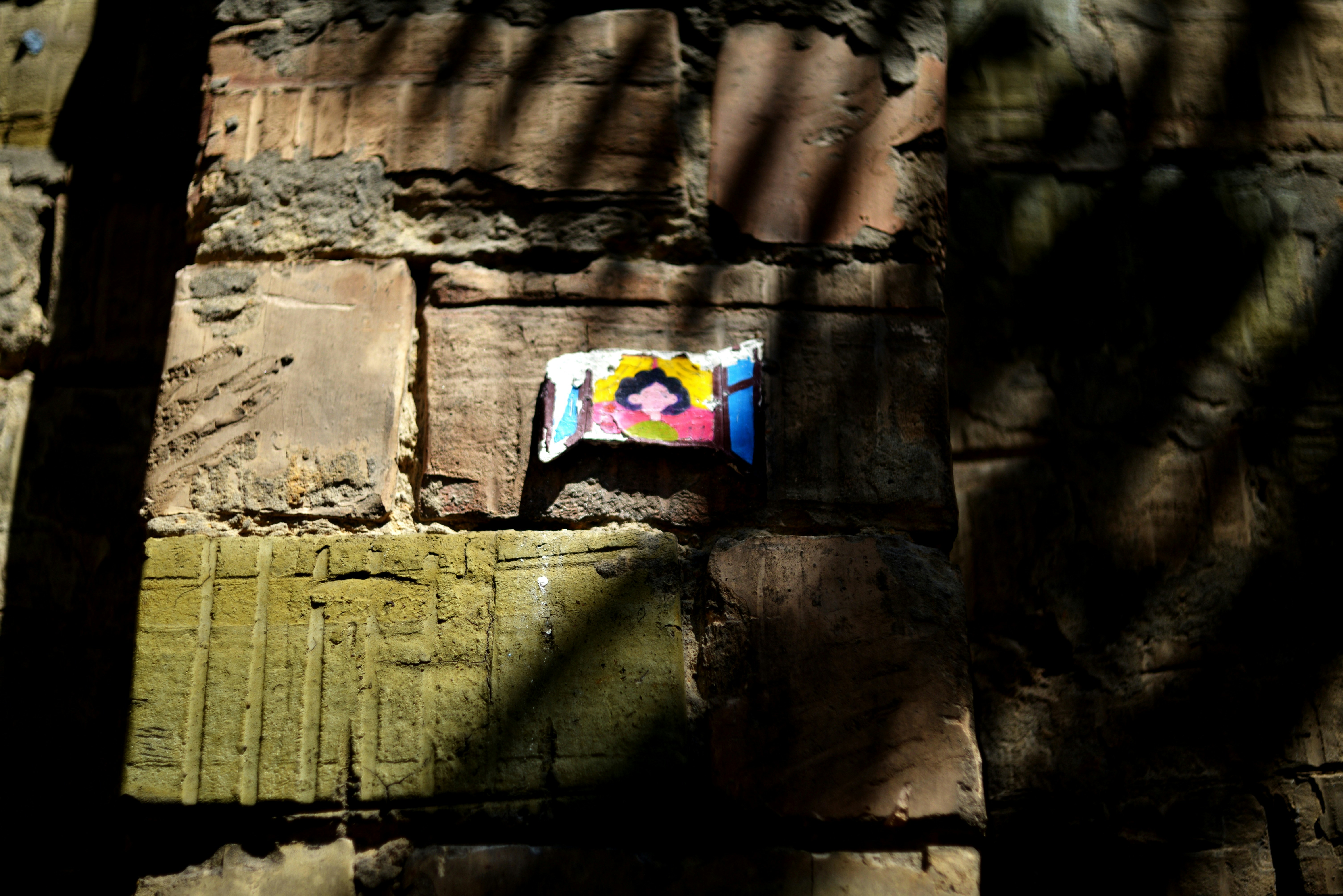 A Tiny Colorful Sticker Anchored on Weathered Brick
