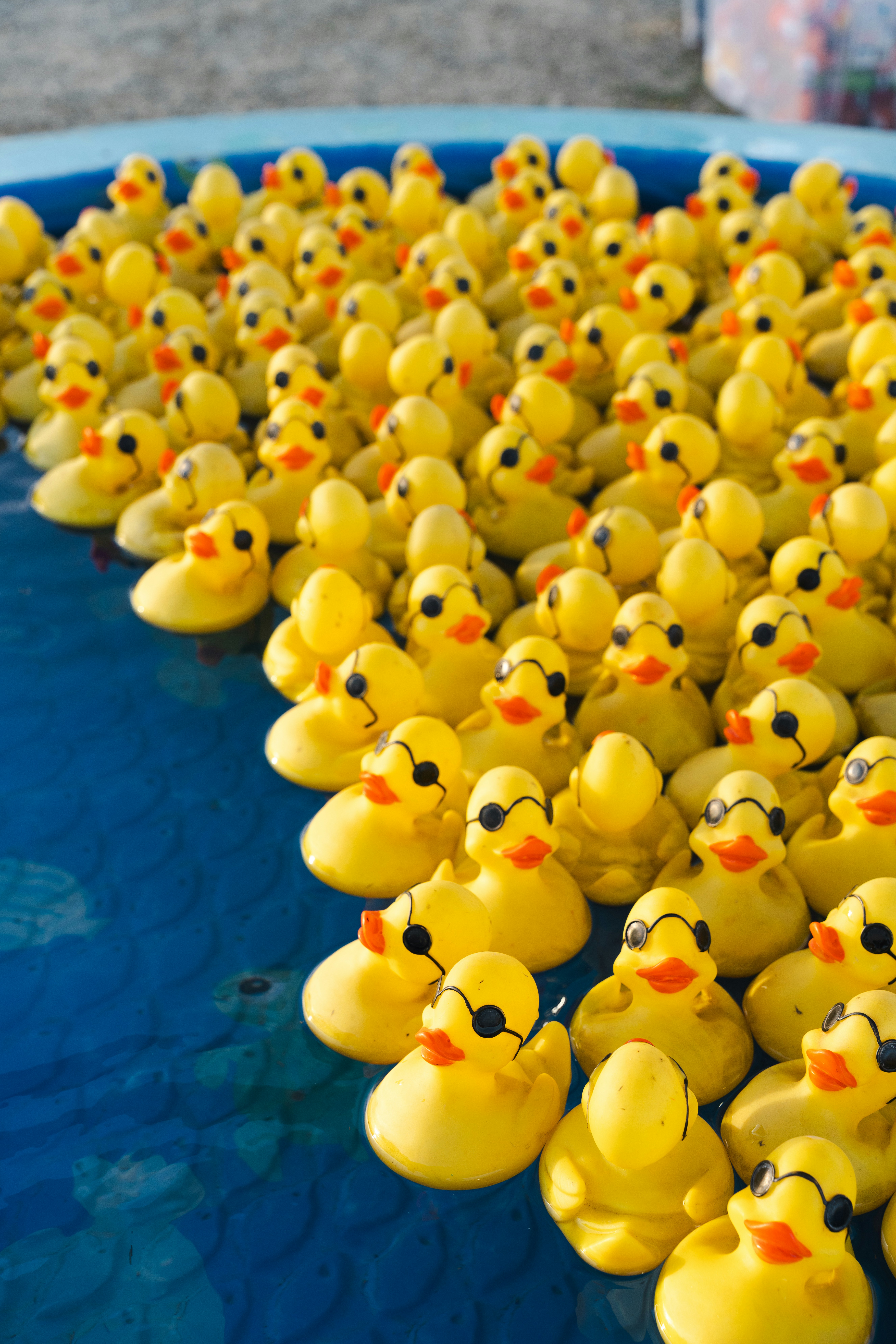 Yellow rubber ducks with sunglasses floating in blue water.