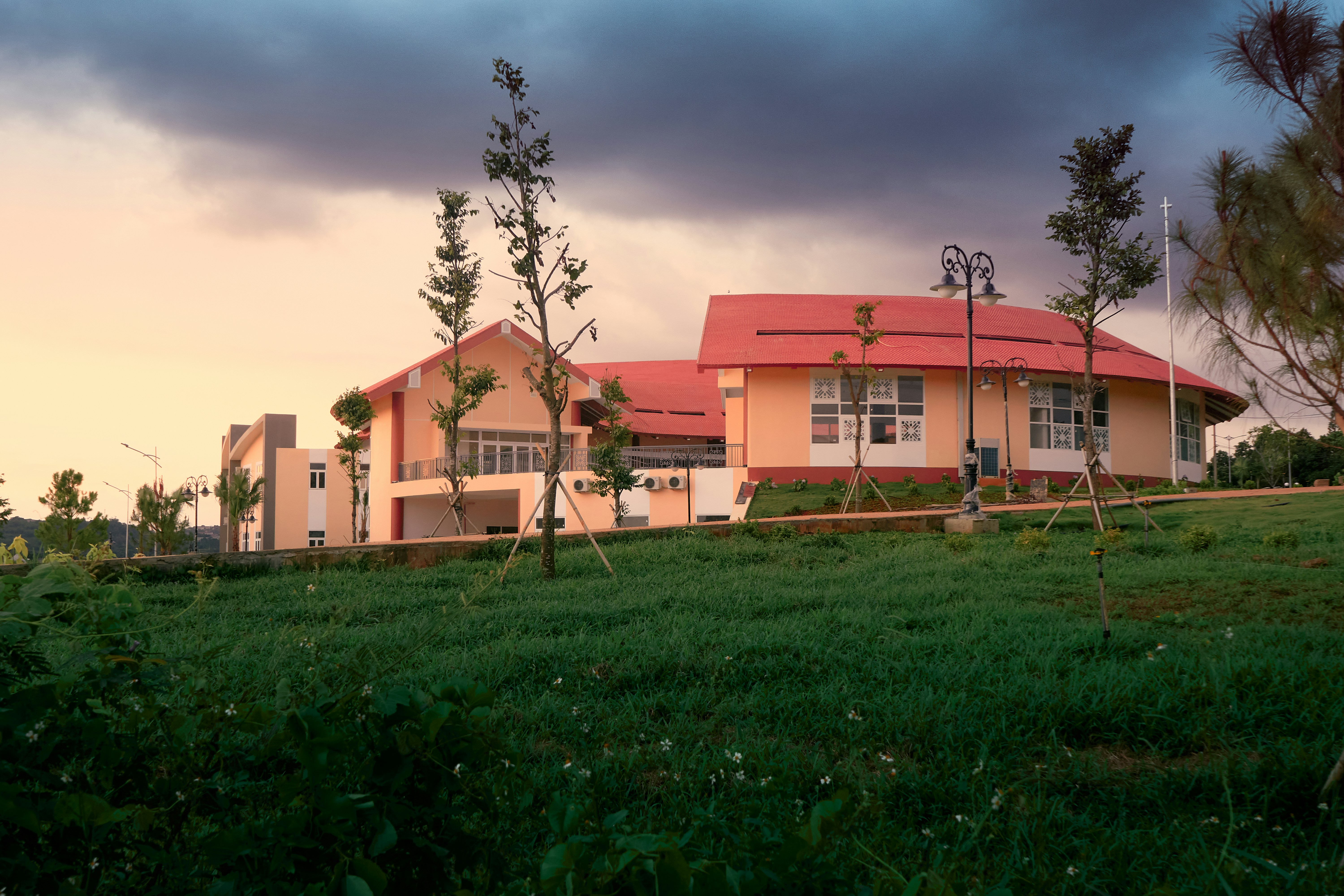 Peach-hued campus at dusk with sloping hill and modern buildings