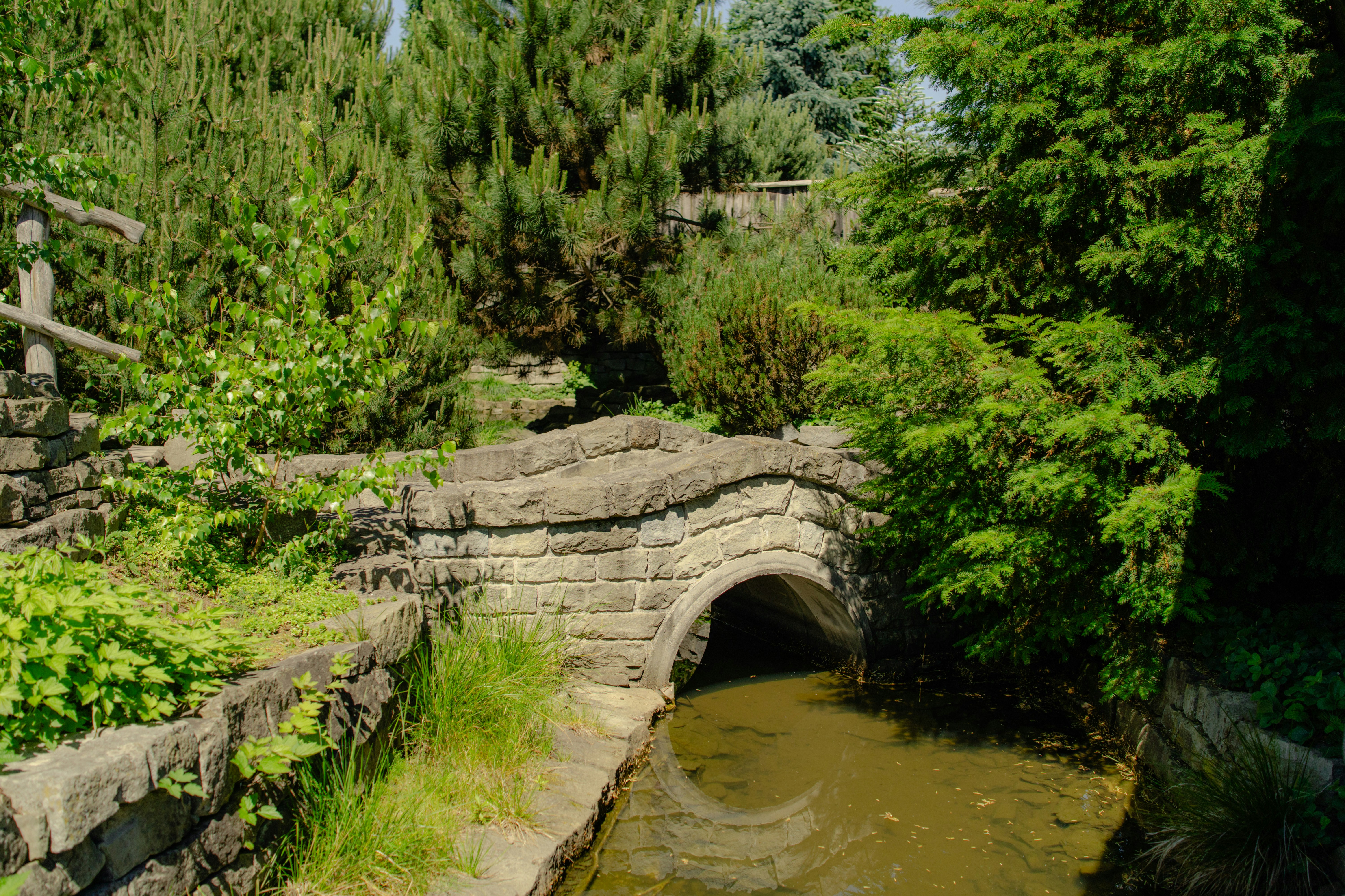 Stone Arch Bridge Over a Quiet Channel in a Lush Garden