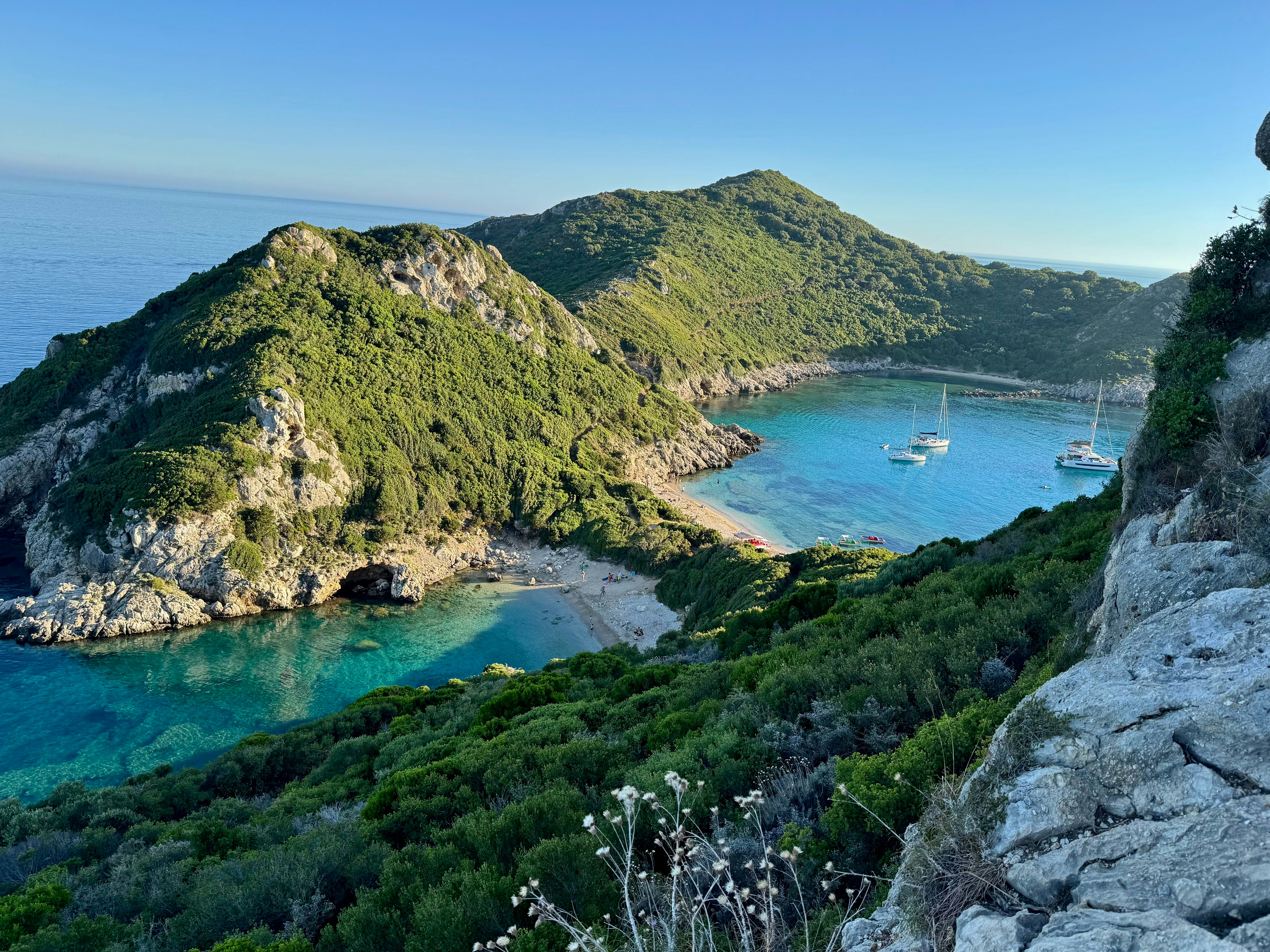 Harbor between emerald cliffs: a sunlit cove with anchored sails