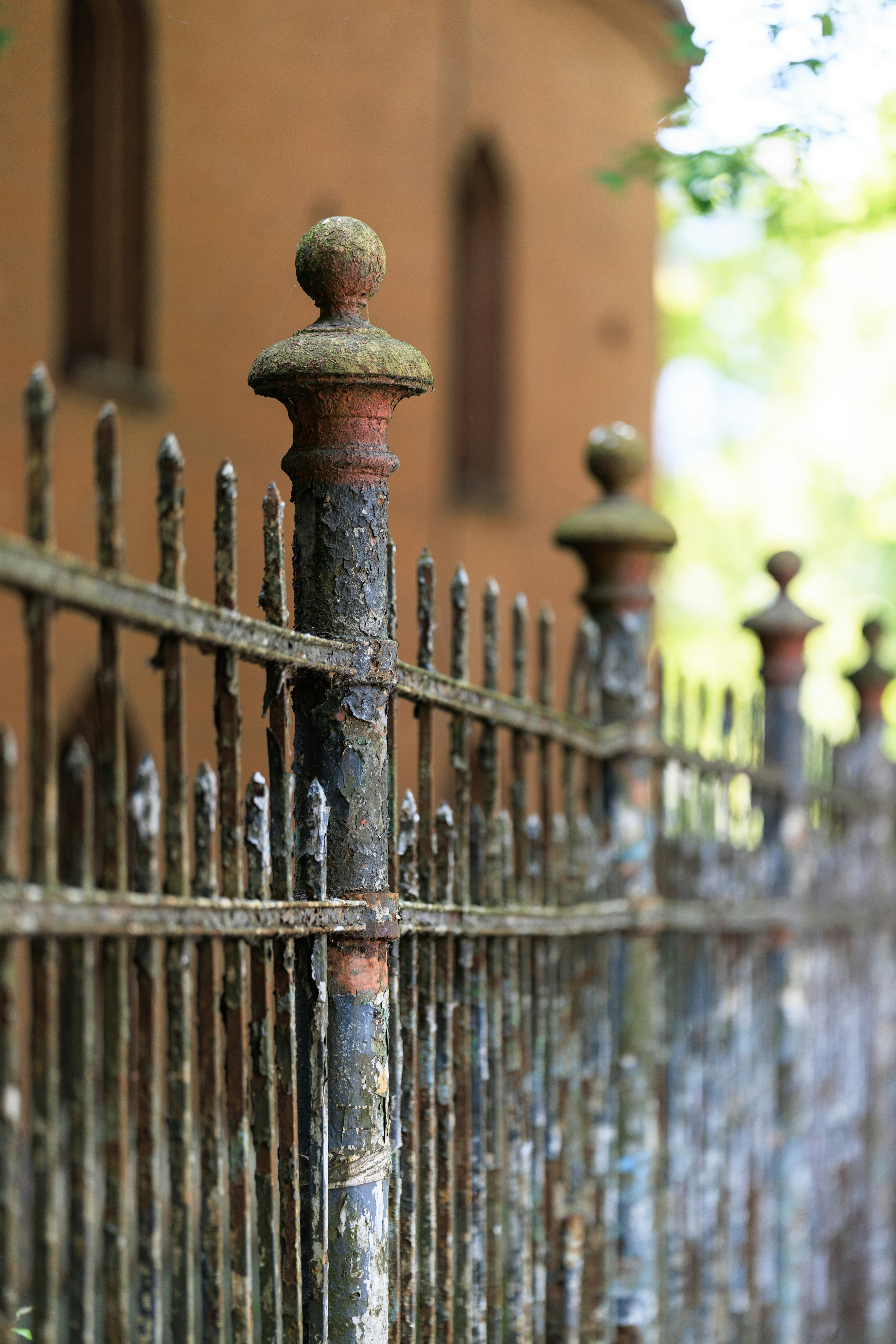 Rust and Rails: An Aged Iron Fence Reaching Toward a Sunlit Murmur