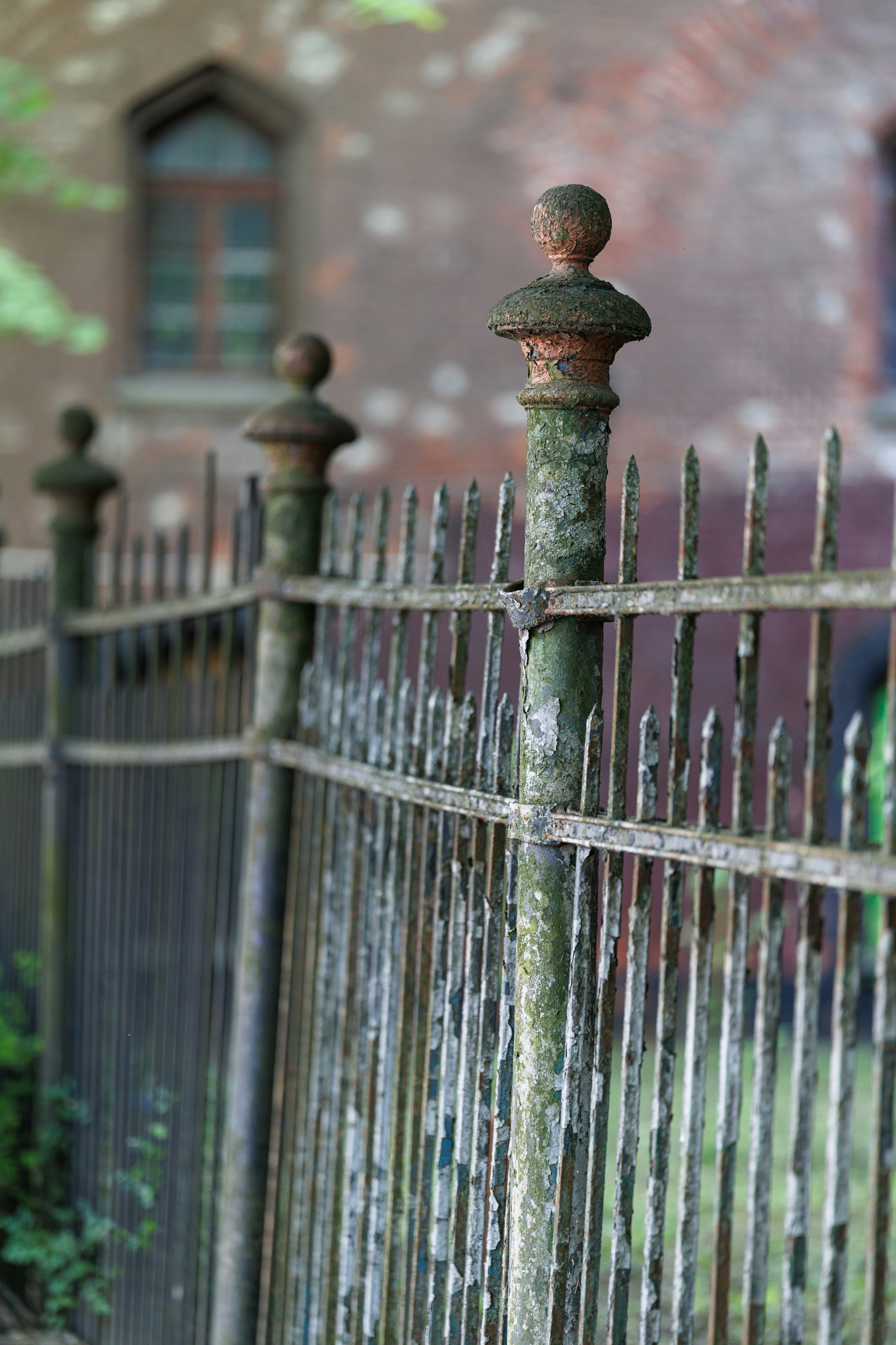 Weathered Ironwork: Mossy Finial Guarding an Old Yard