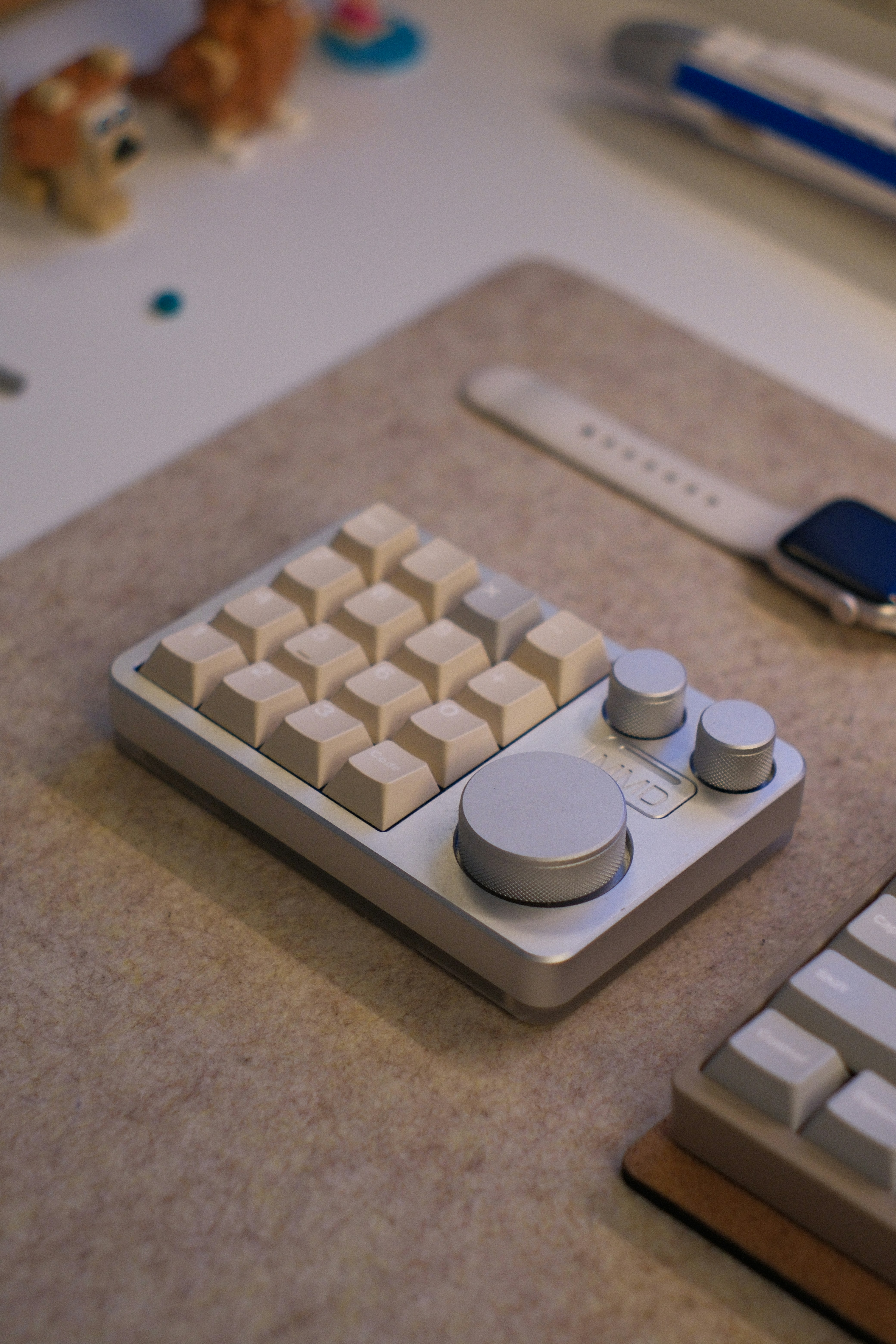 Quiet workstation: a compact keyboard, dial knobs, and smartwatch on a felt mat