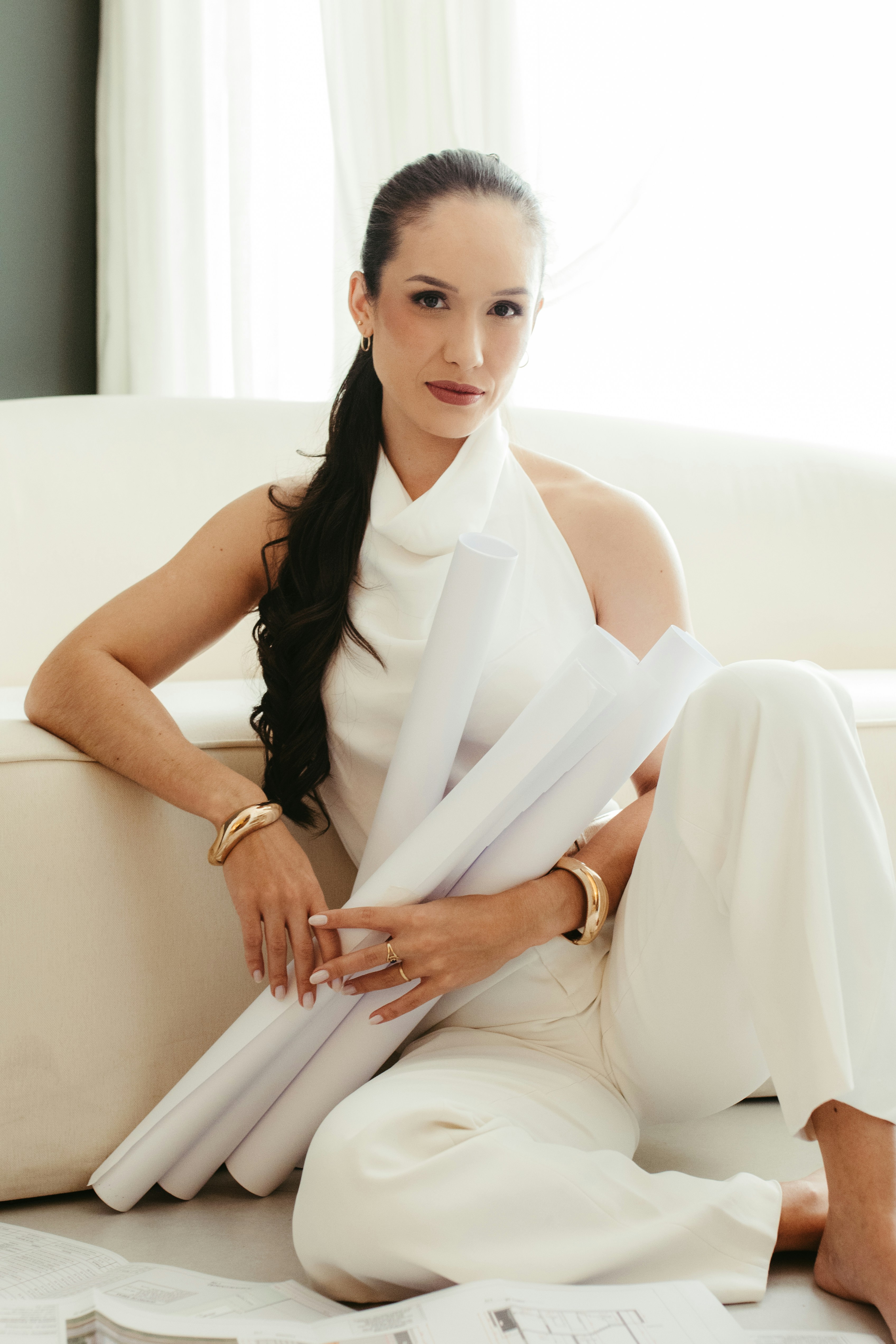 Elegant silhouette: a poised woman in white with rolled plans
