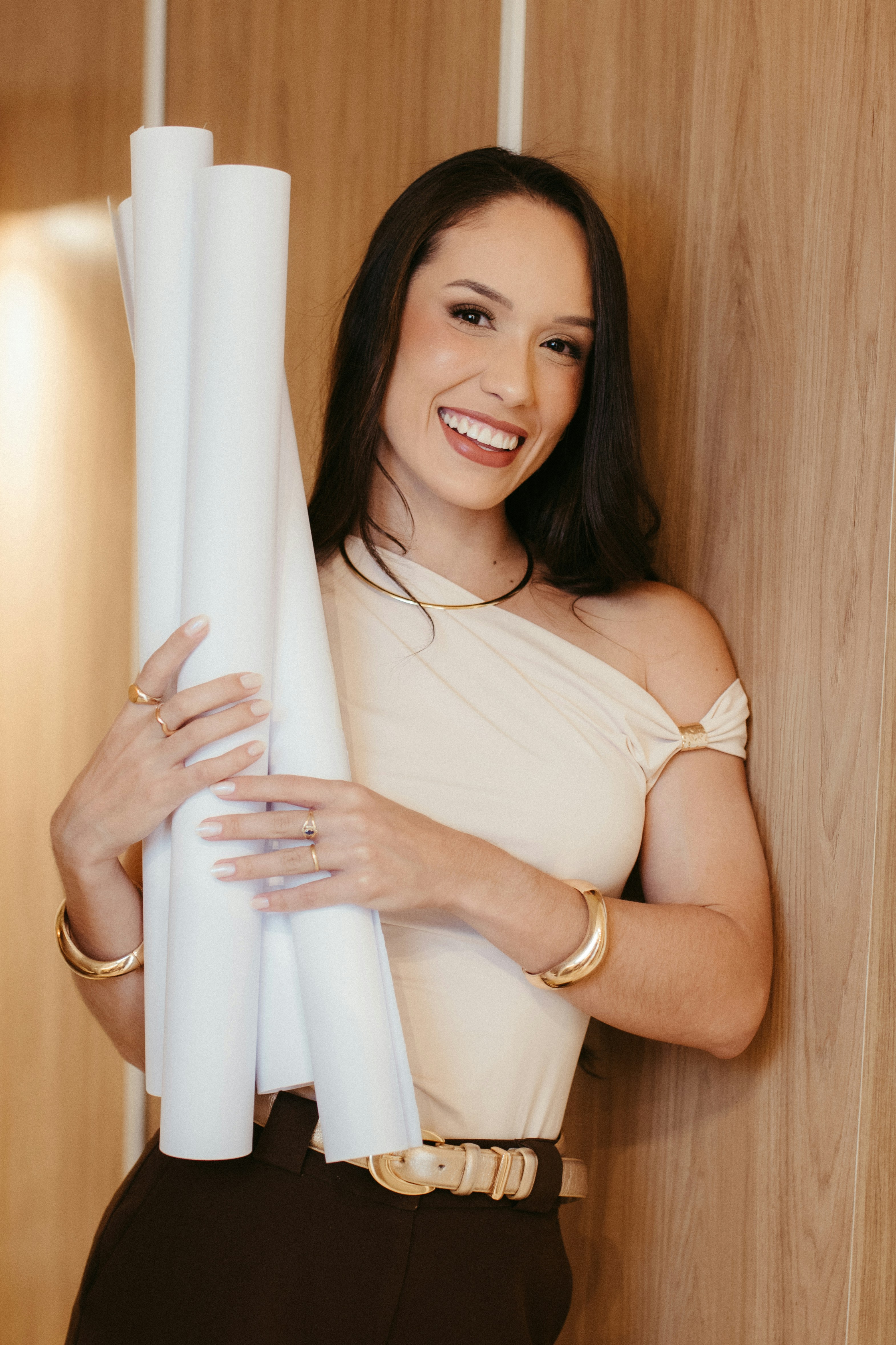 Bright smile and rolled plans: portrait of a cheerful designer in a cozy hallway