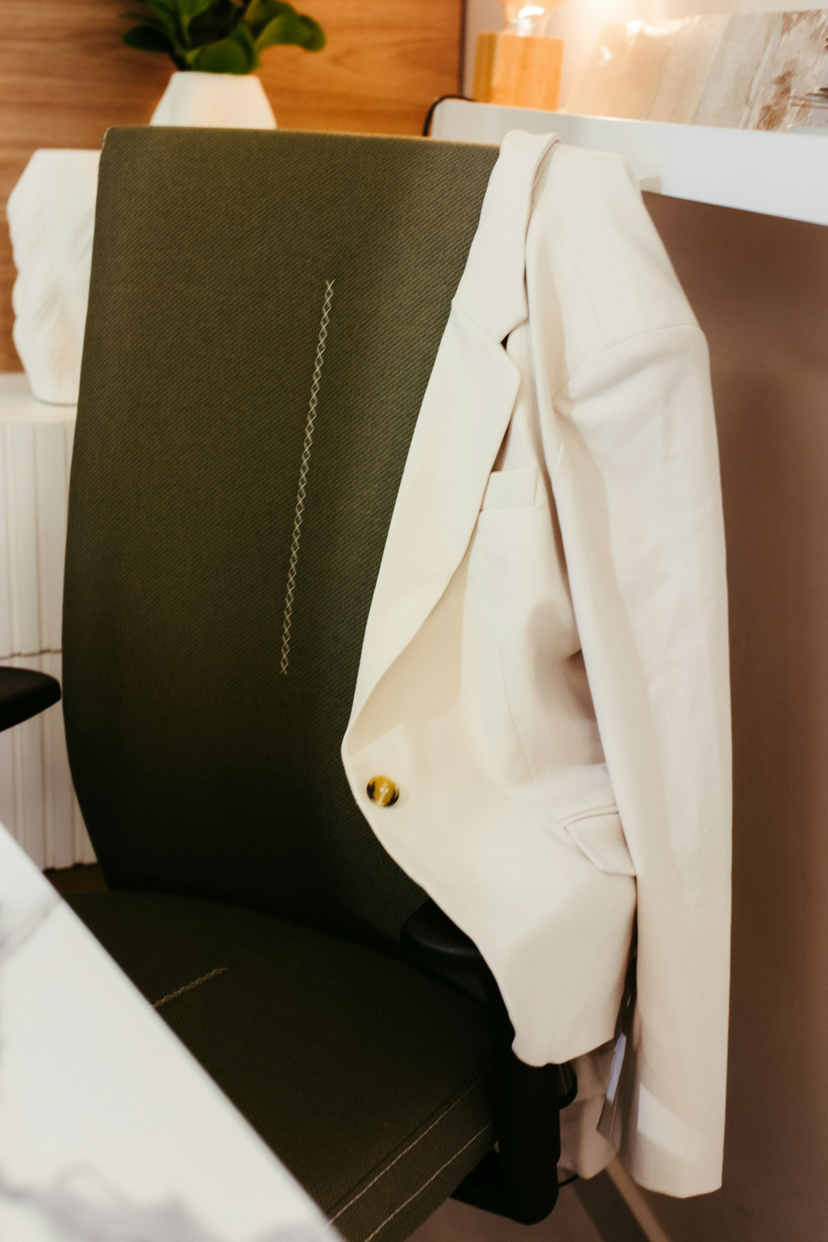 White blazer draped over a dark office chair in a tidy workspace