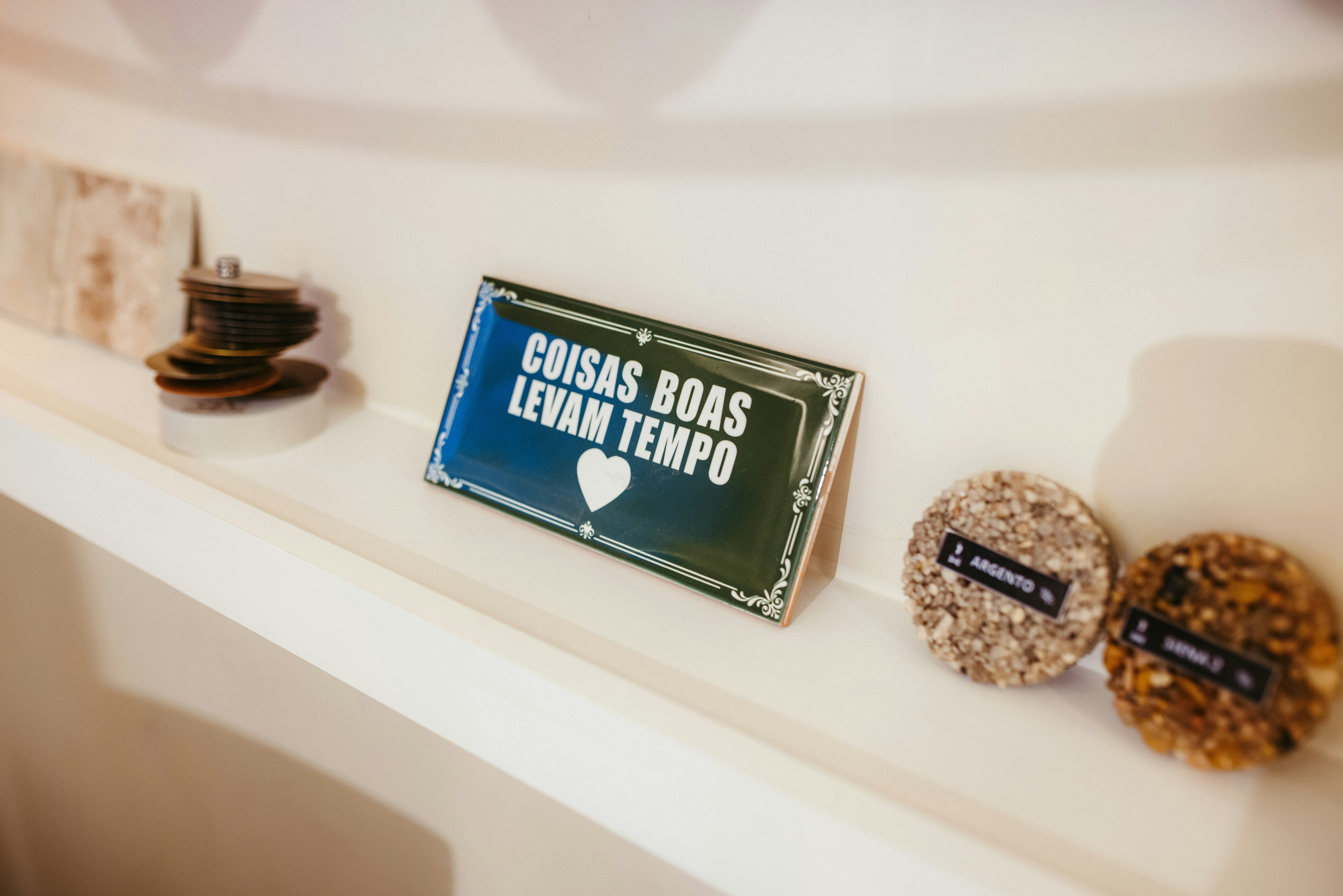 Decorative sign 'coisas boas levam tempo' on a white shelf.