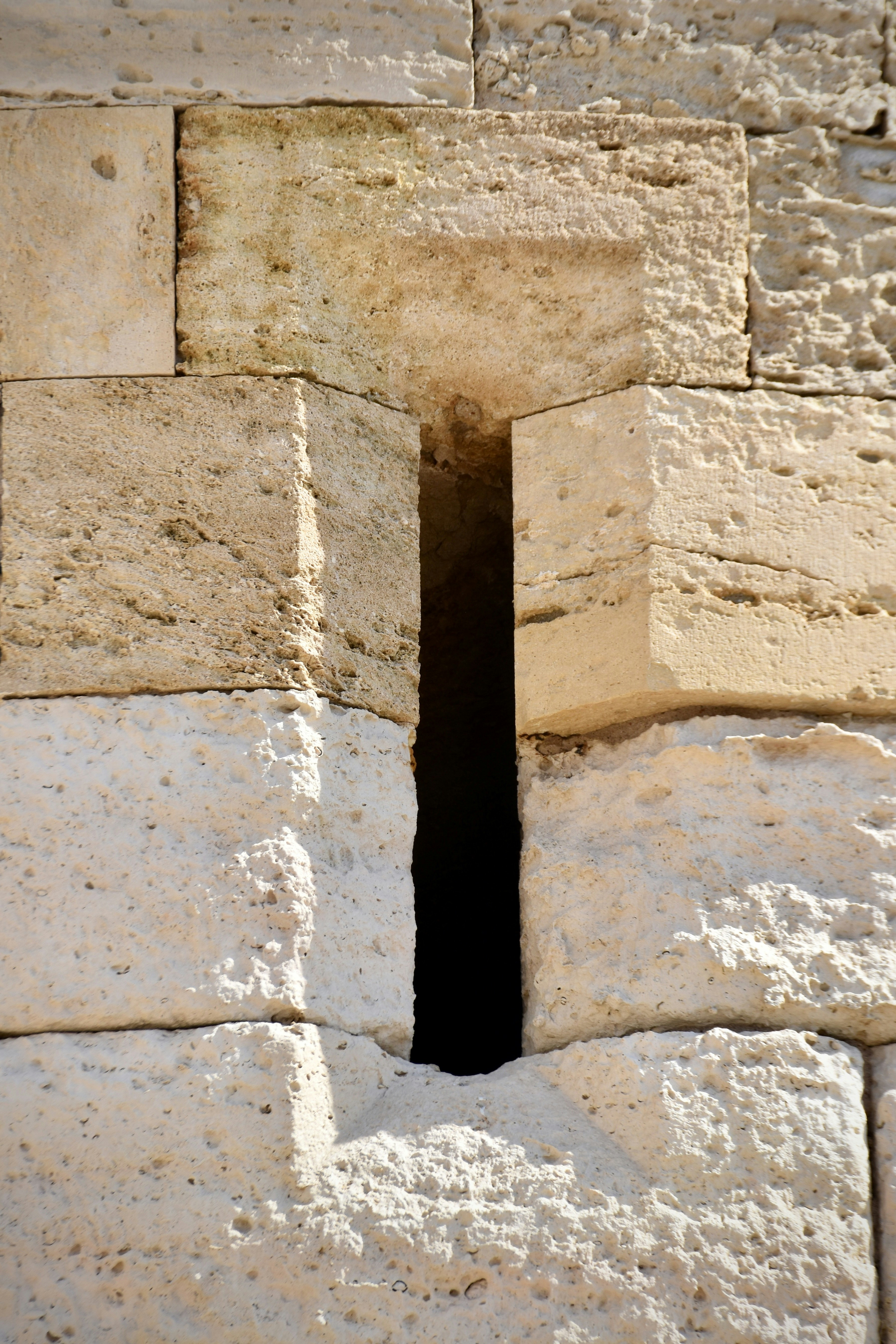Ancient Stone Aperture: Sunlit Narrow Gap Between Weathered Blocks