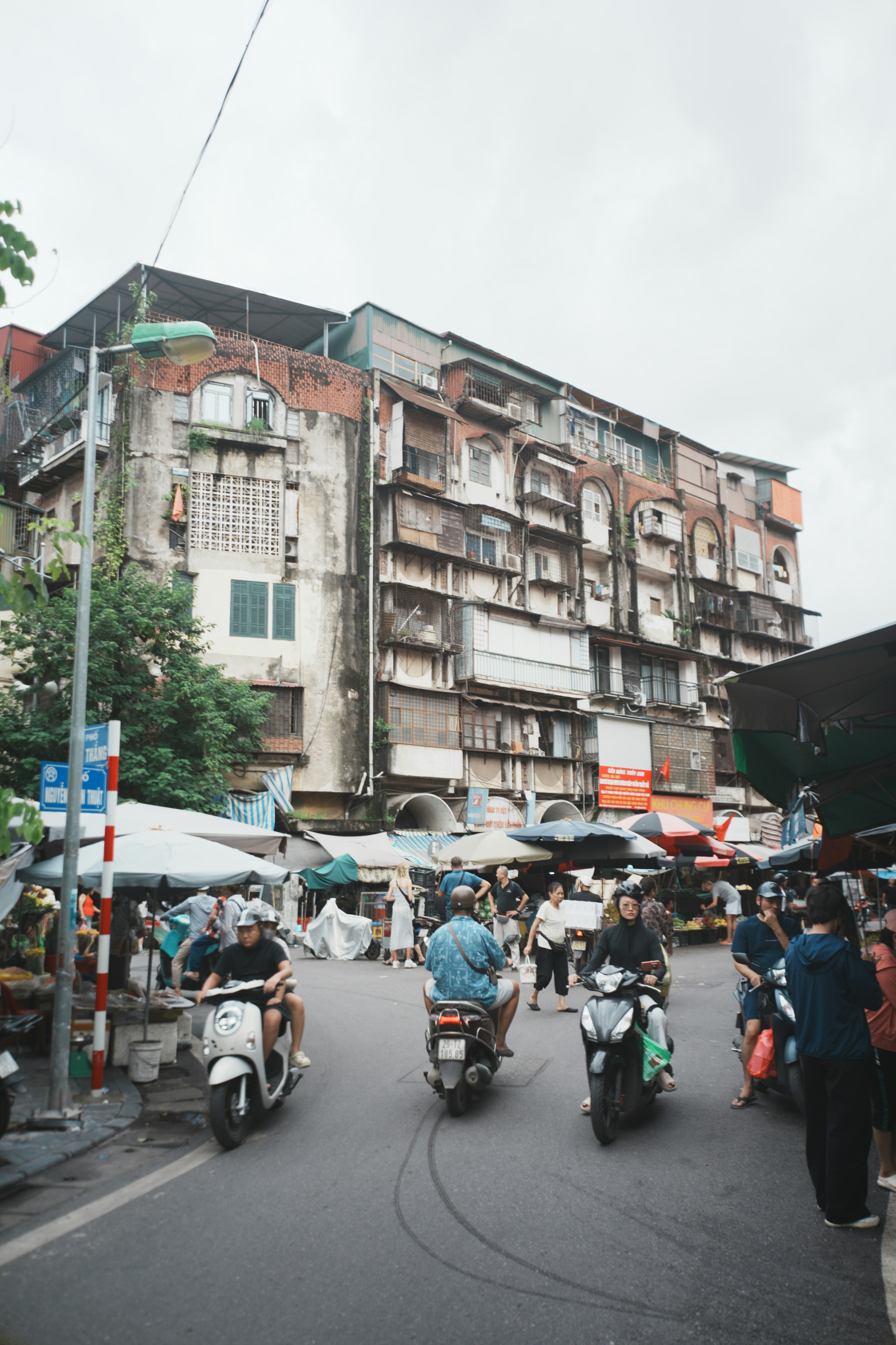 Street Market Chorus Beneath a Weathered Apartment Facade