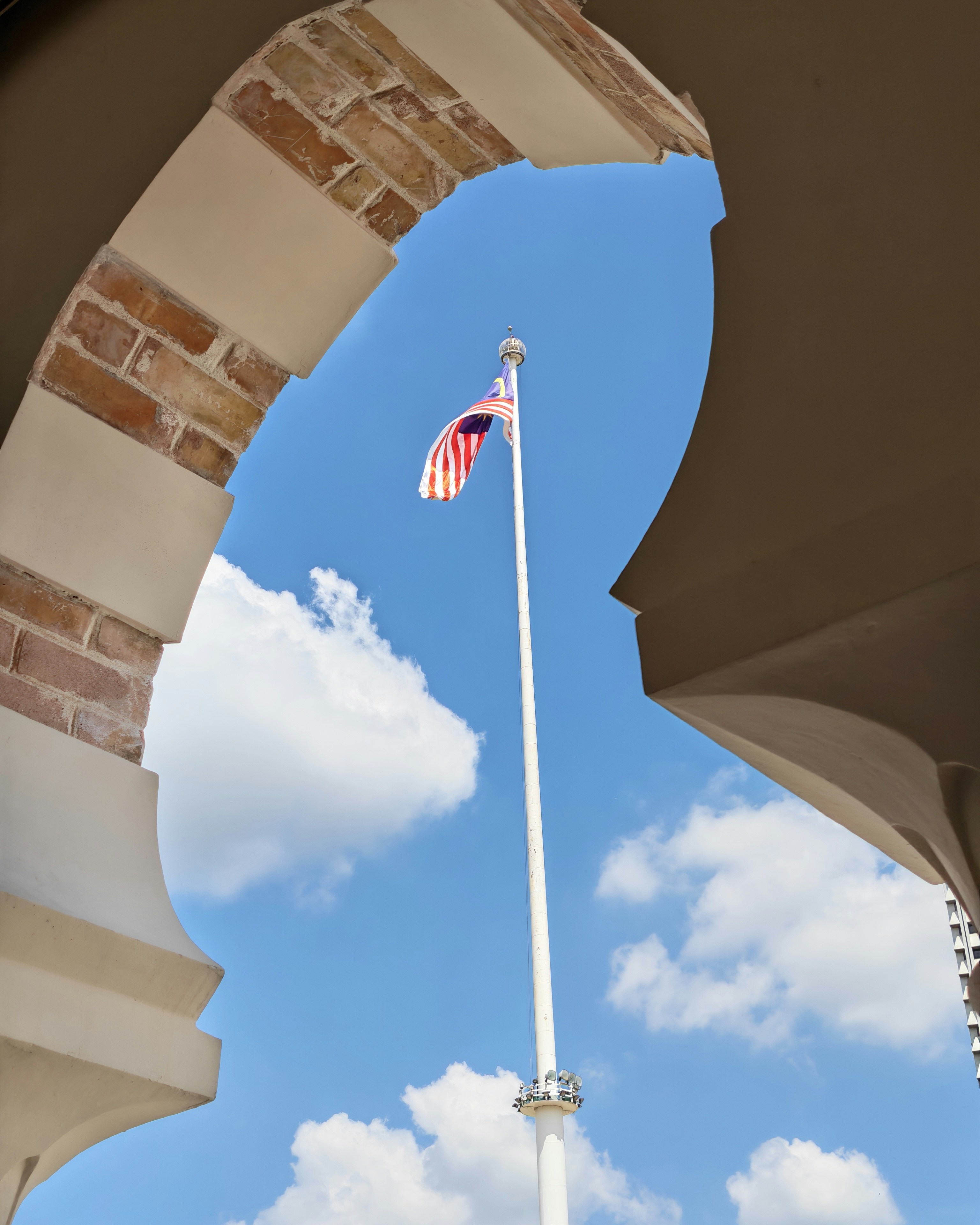 Flag against a carved arch: skyward focus through architectural frame