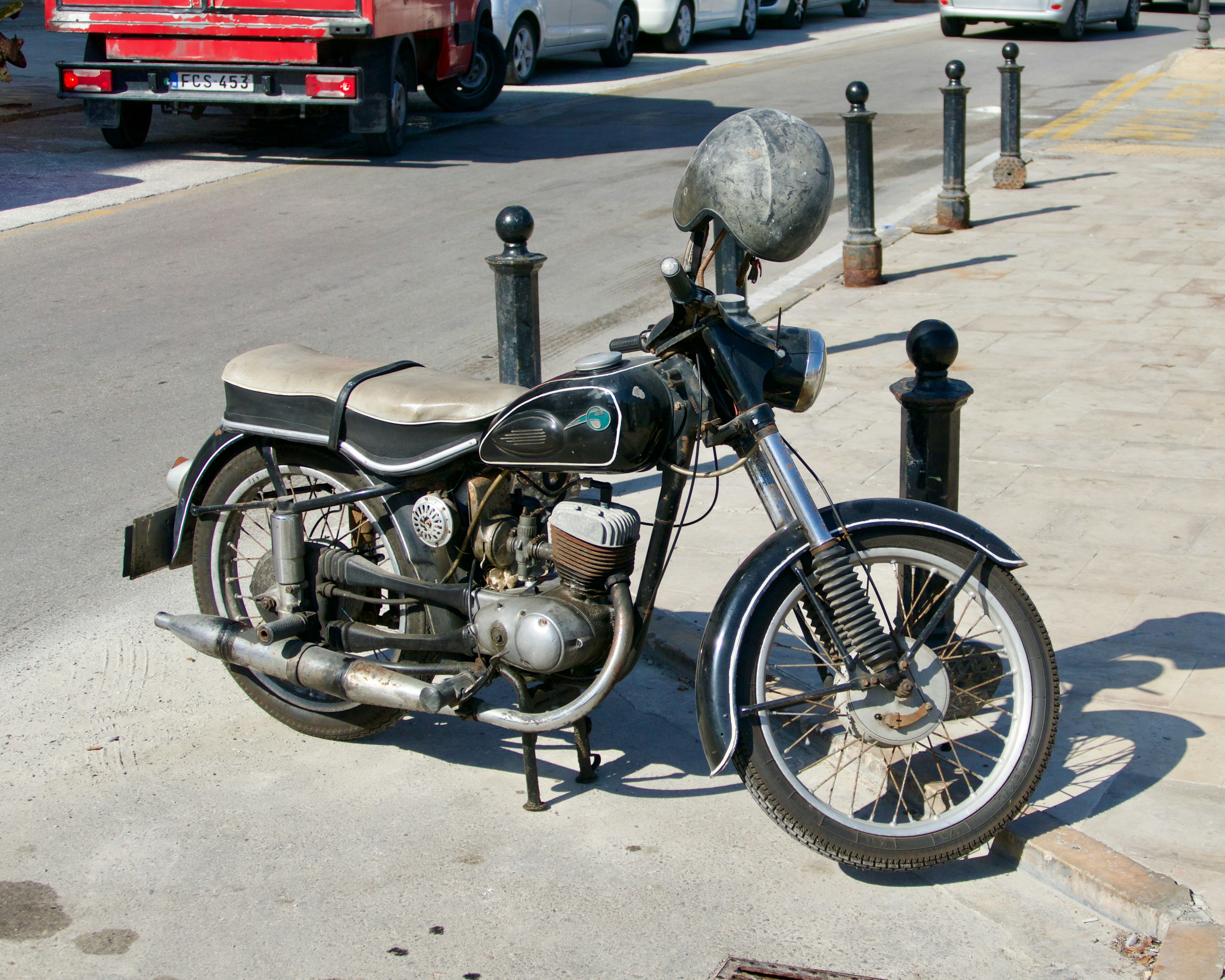 Antique Motorcycle Resting by the Curb: Weathered Steel and Shadowed Chrome