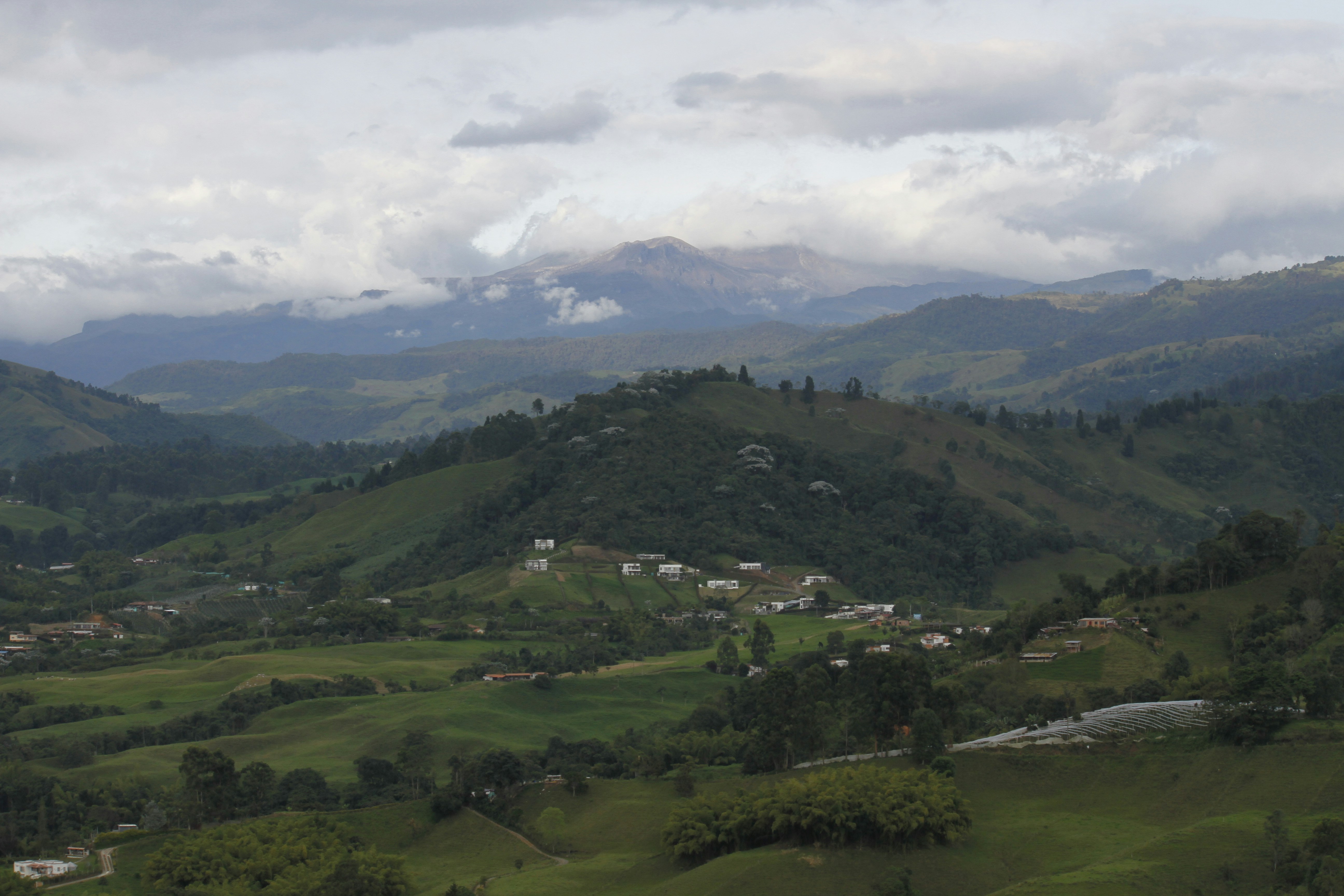 Rolling Hills and Distant Ridge Under Clouded Sky