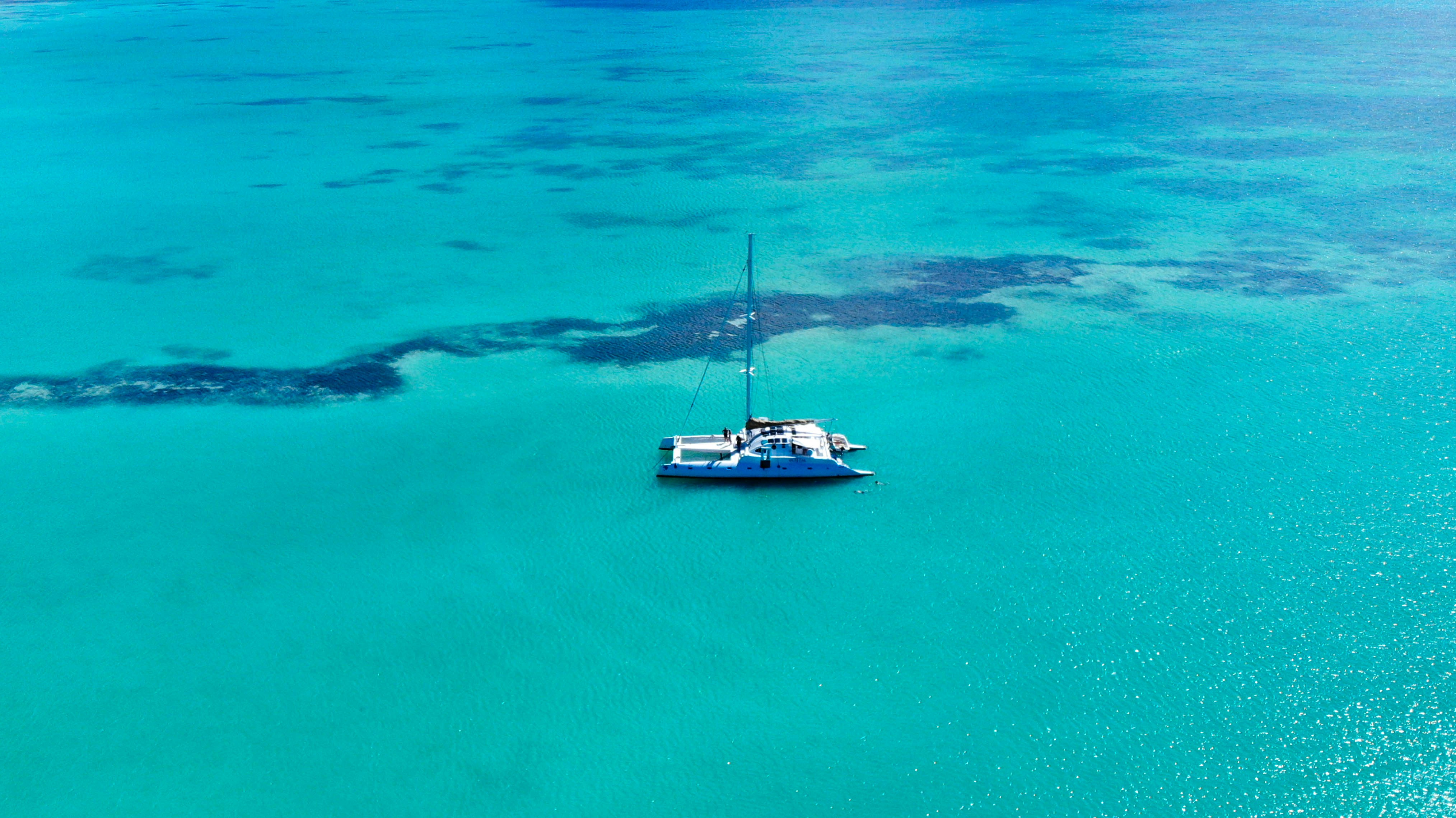  solitary sailboat amid crystal turquoise shallows