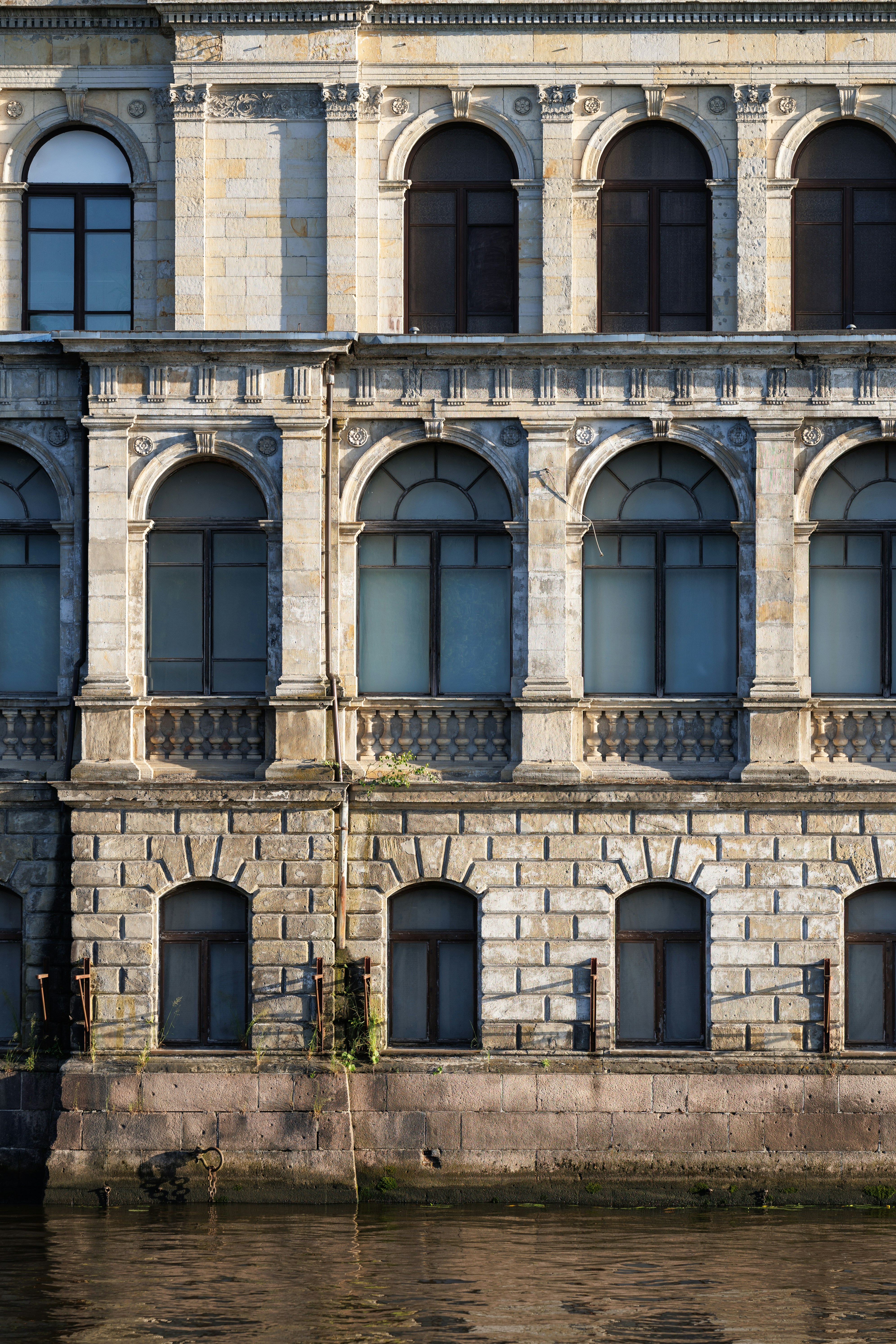 Stone Facade by the Water: Arched Windows and Riverbank