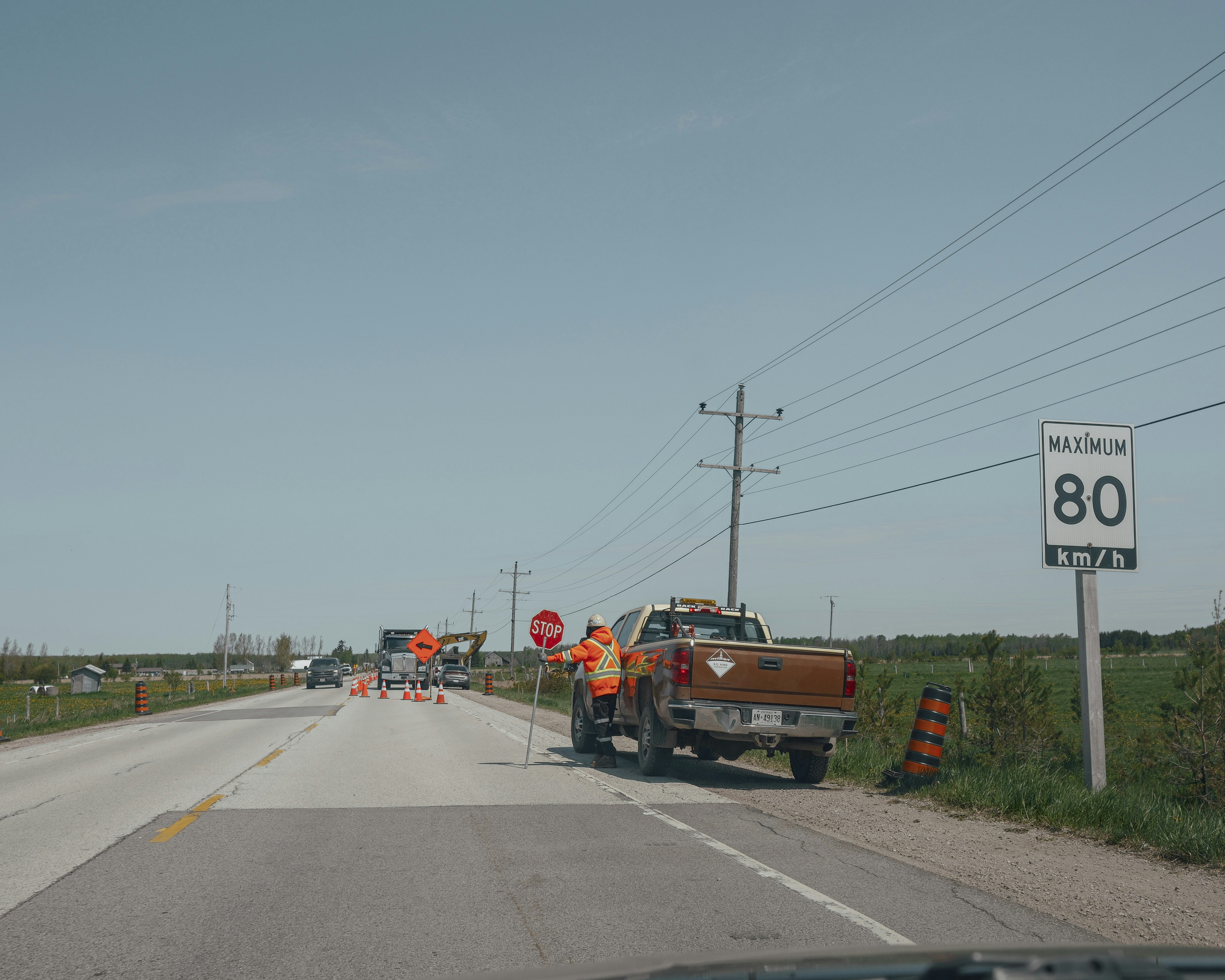 Roadwork Vigil: Stalled Pickup and Highway Sign in a Quiet Corridor