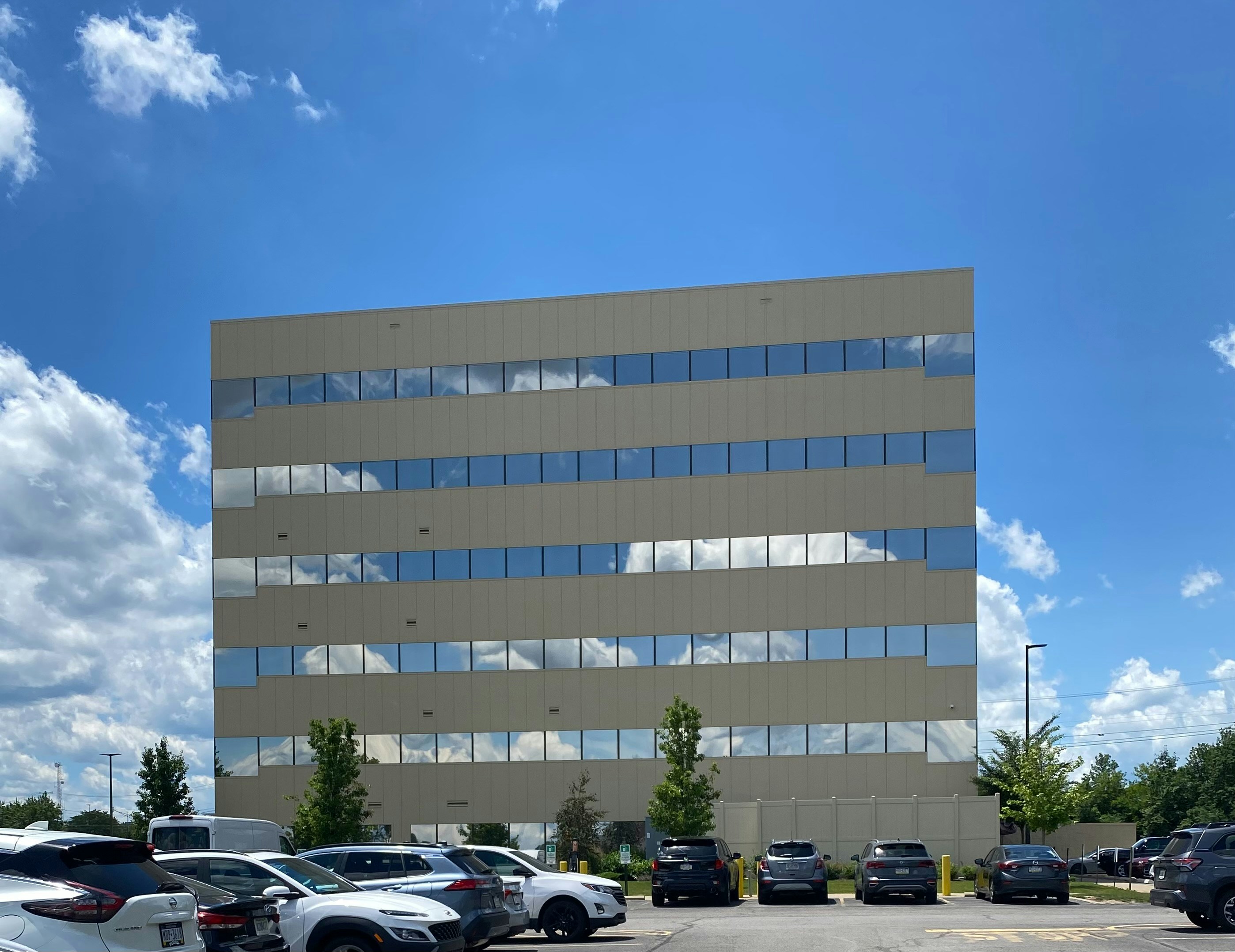 Glass-and-Concrete Office Tower Reflecting Sunlit Sky