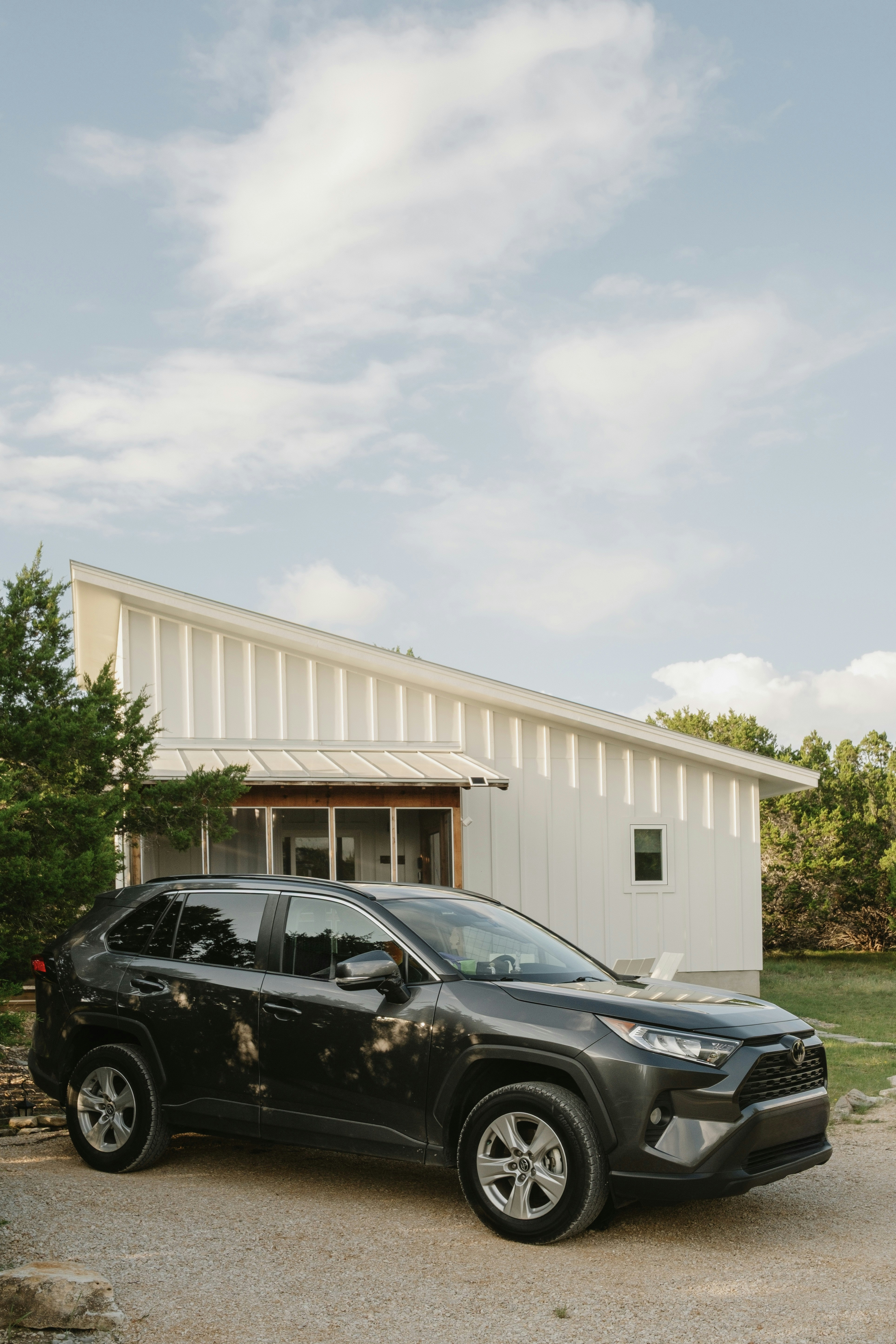 Black SUV in front of a modern white building under a blue sky