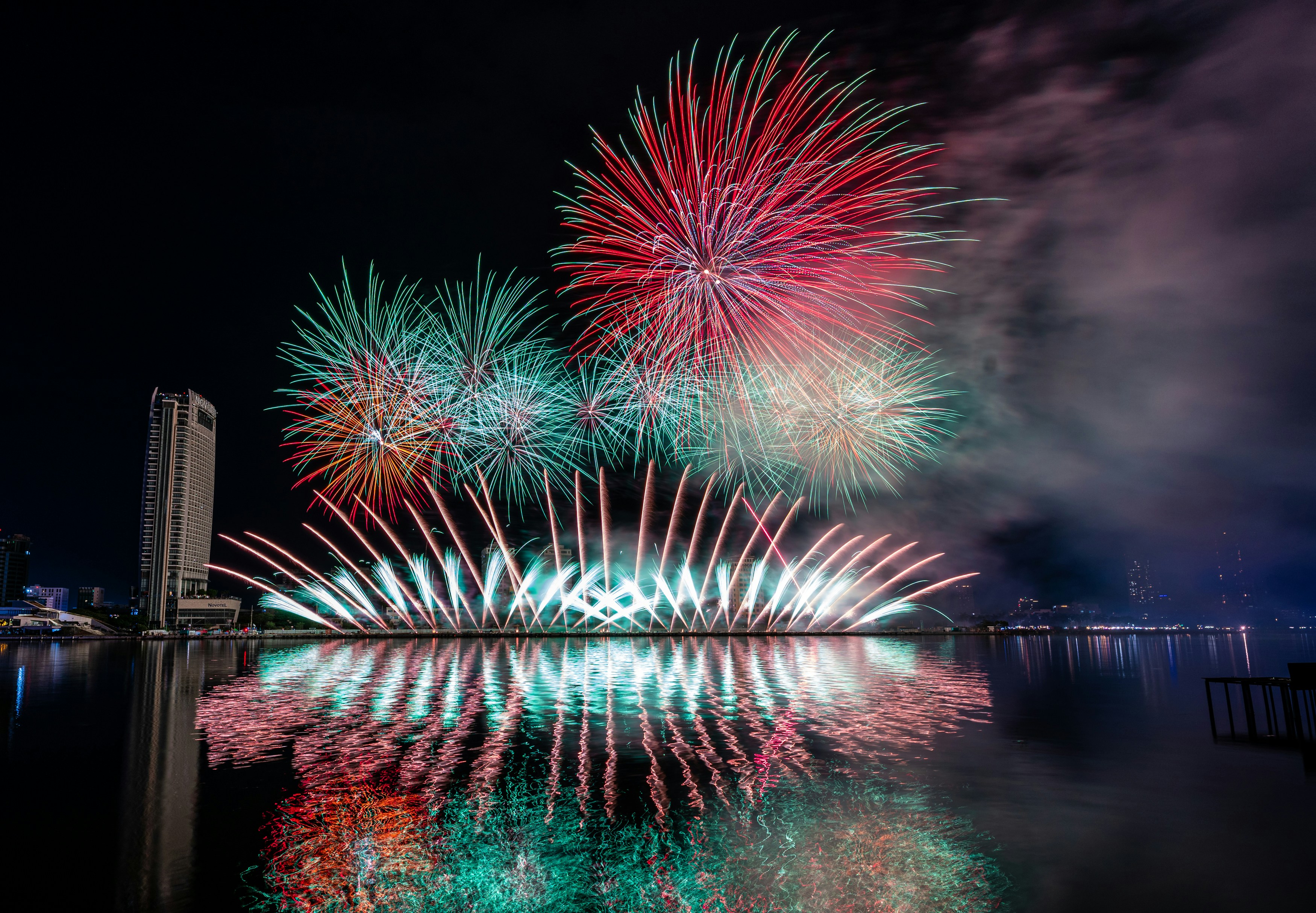 Night Bloom: Fireworks Over Water Reflecting a City Skyline