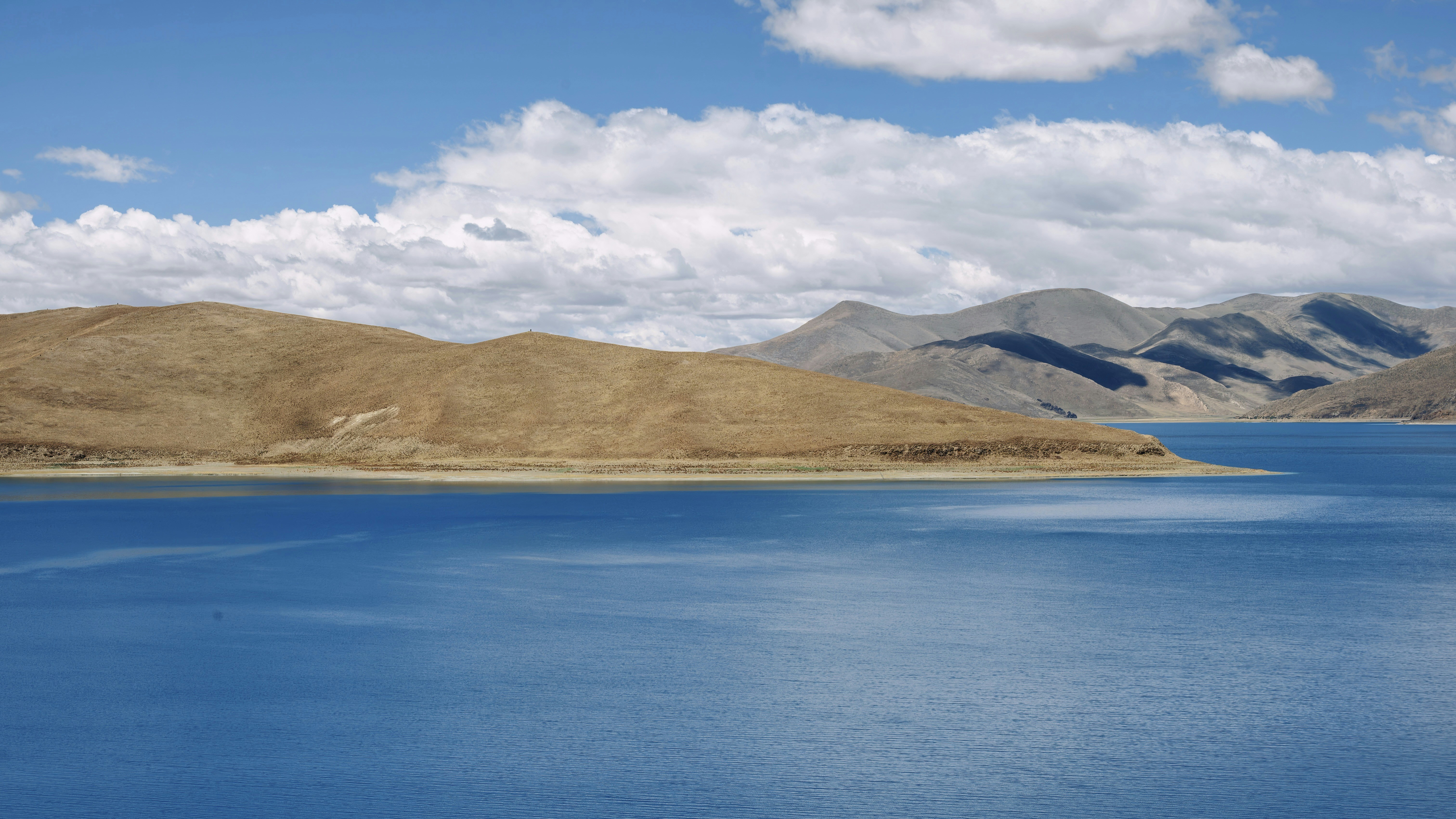 Lone Blue Reservoir with Golden Hills under a Cotton Sky