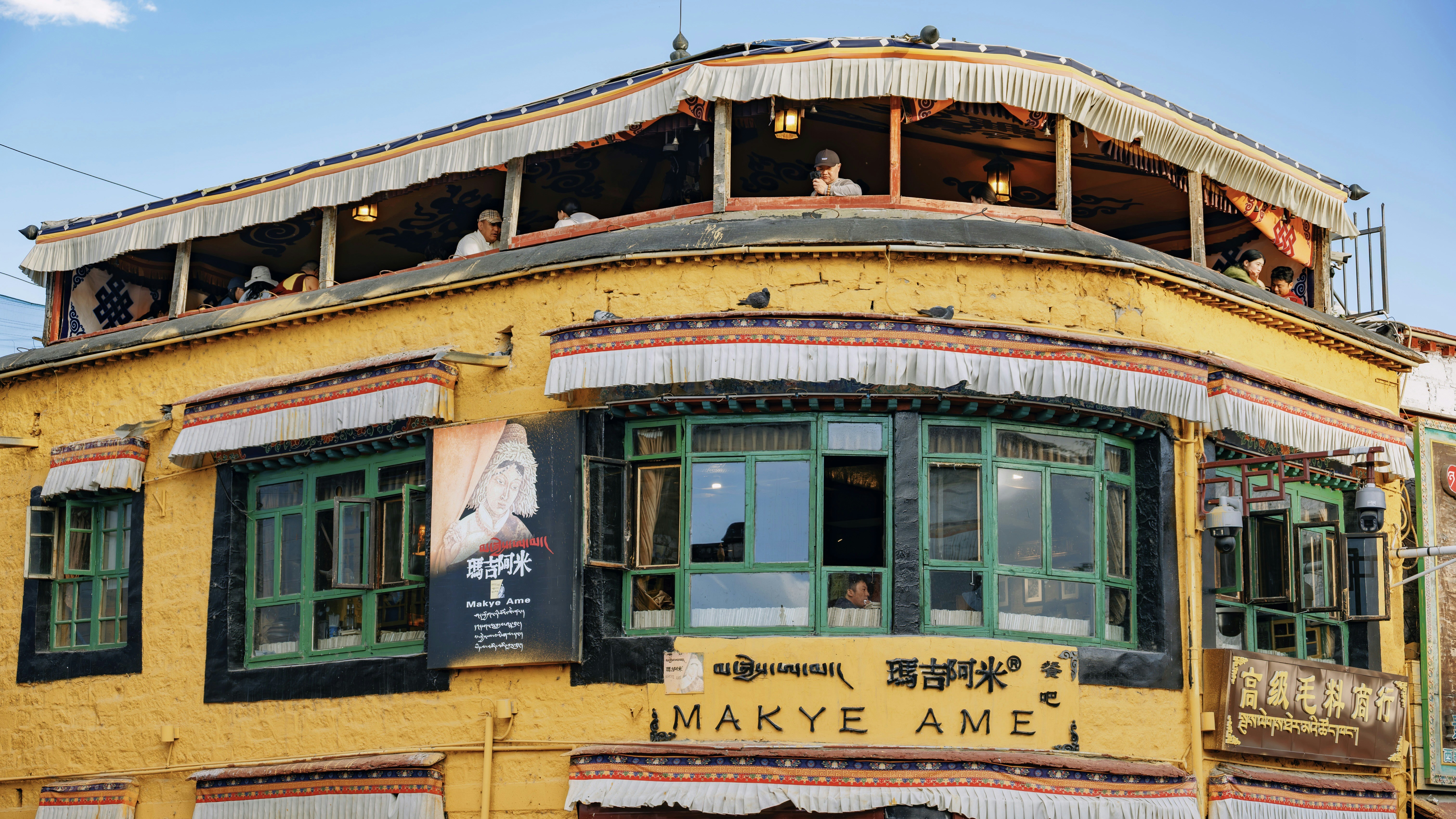 Yellow Cornered Café: People Watching from a Veranda Above a Faded Eatery
