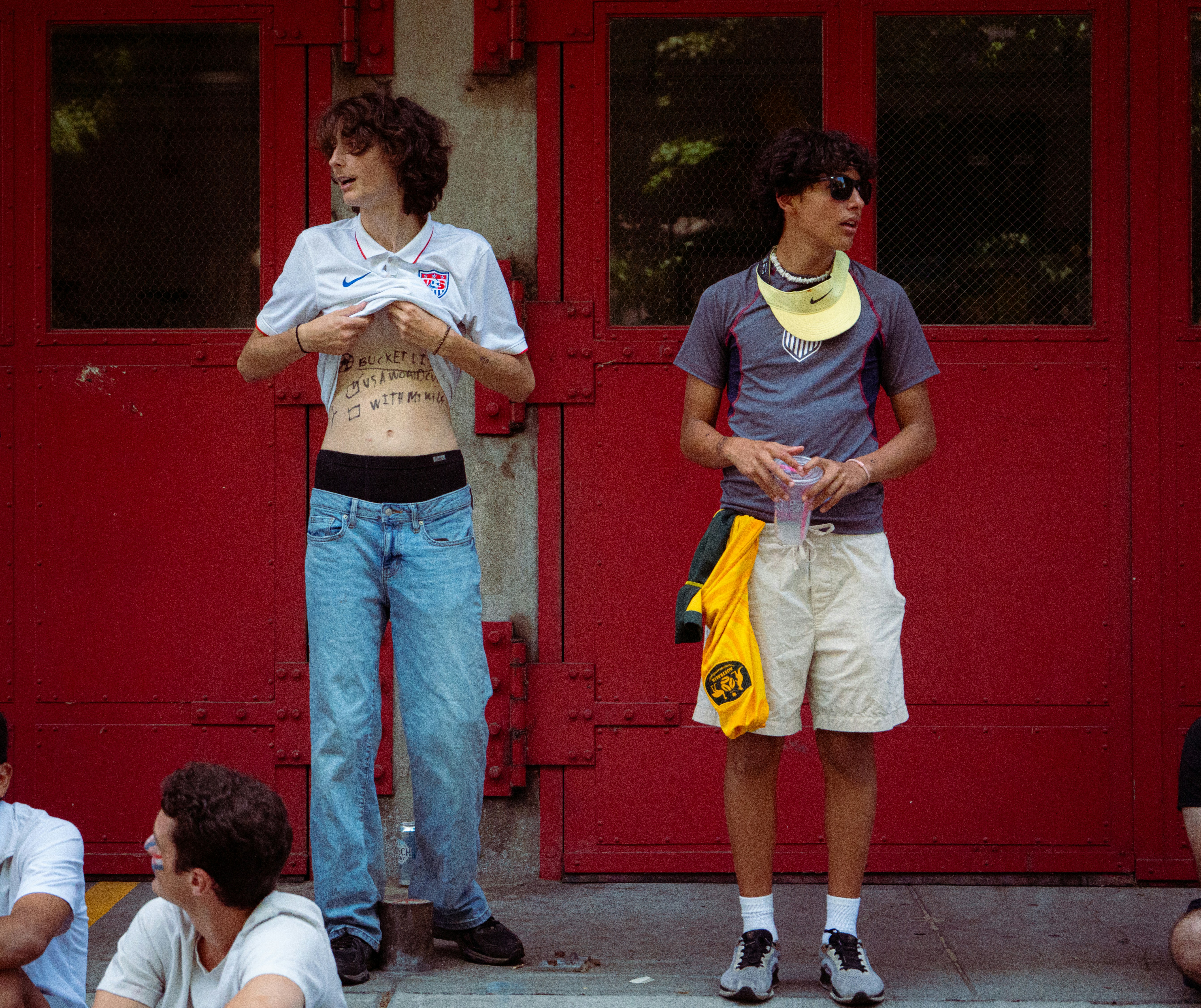 Red Doors, Quiet Rebellion: Two Teens Stand Defiant in the Courtyard