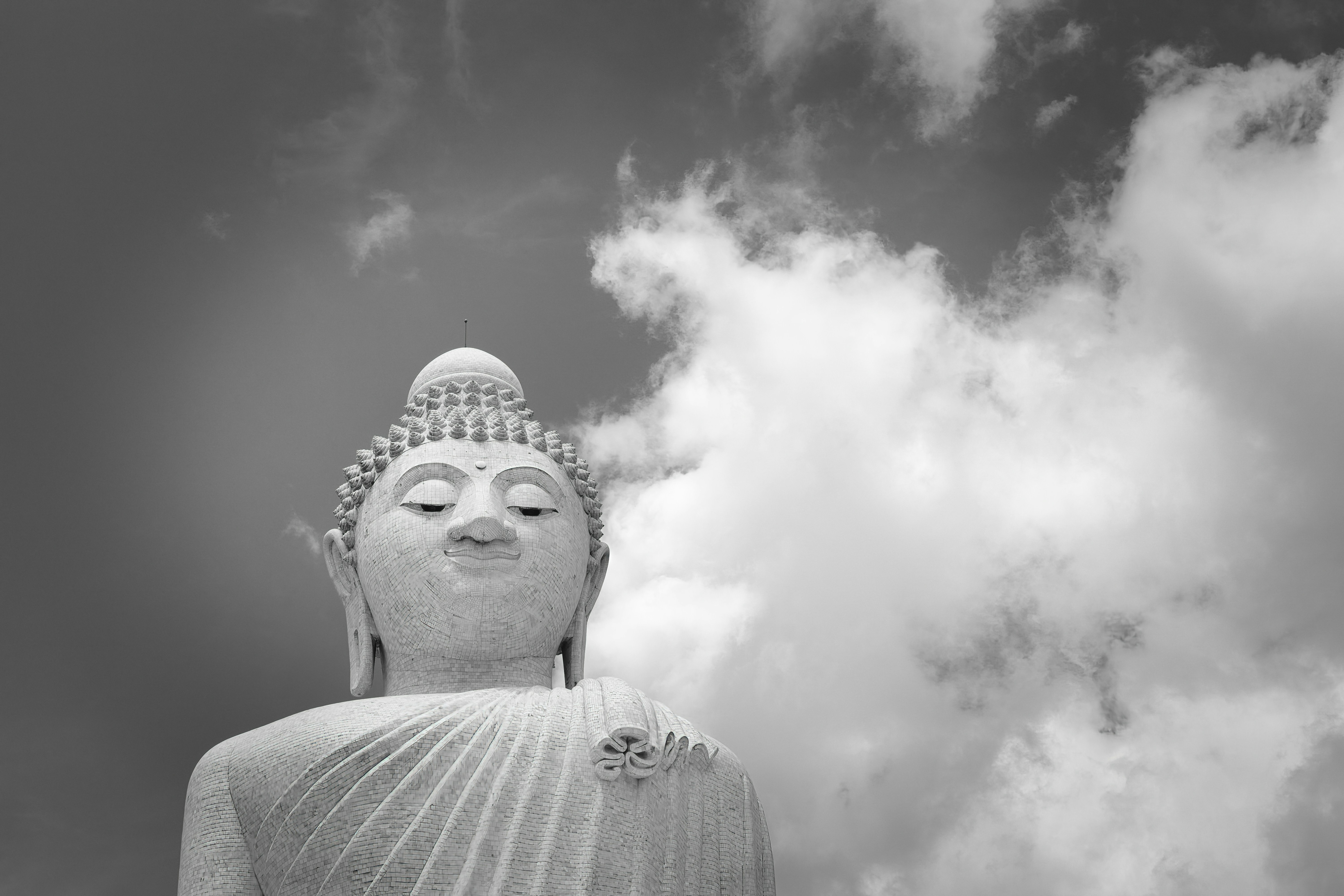 Silhouette of Serenity: A Buddha Statue Against Soaring Clouds