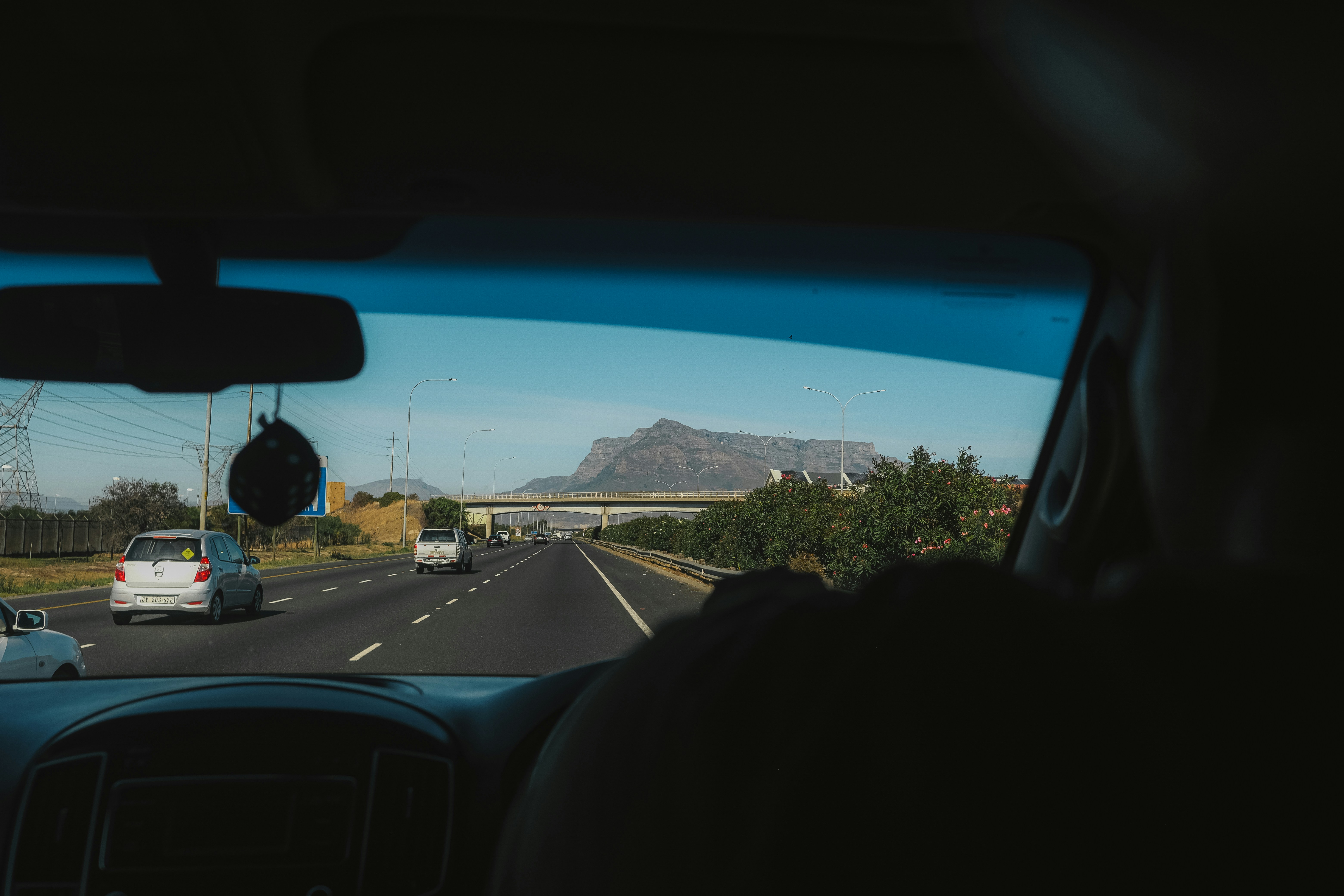 Road to Distant Peaks: A Car Interior View Under Open Sky