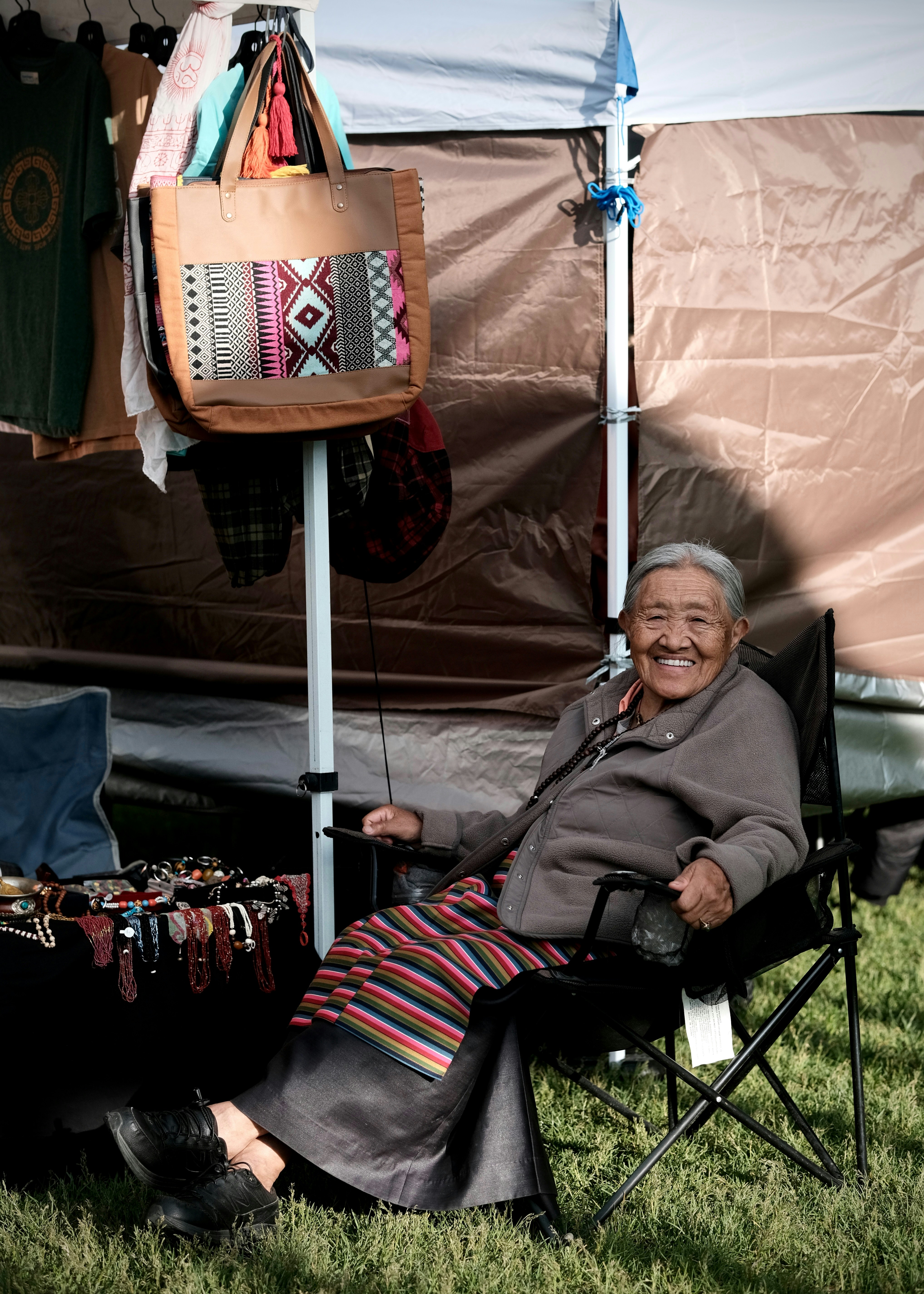 Smiling Elder in a Market Tent: Colorful Goods and Heritage Fabrics
