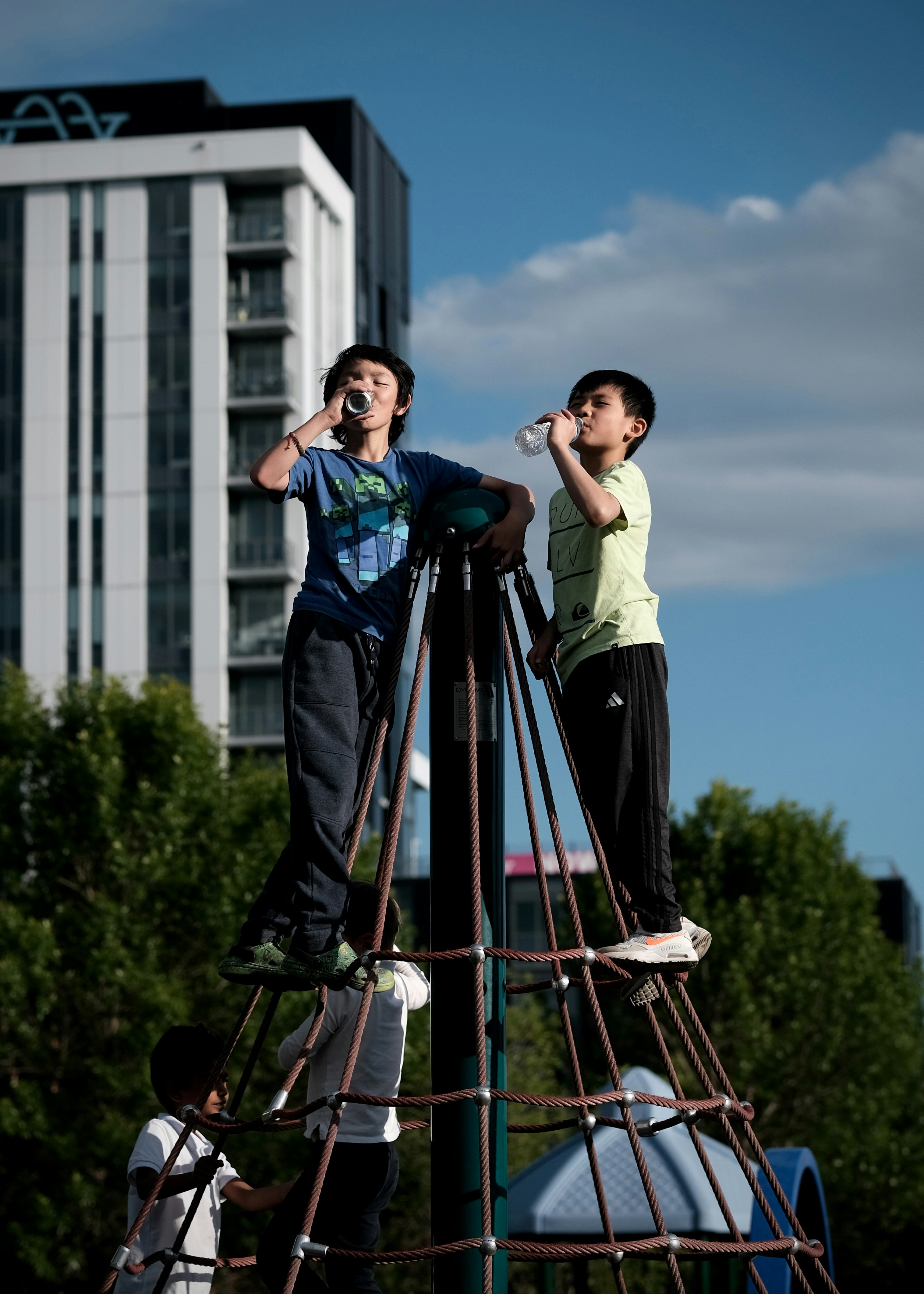 Two Boys on a Rope Pyramid Overlook a Cityscape