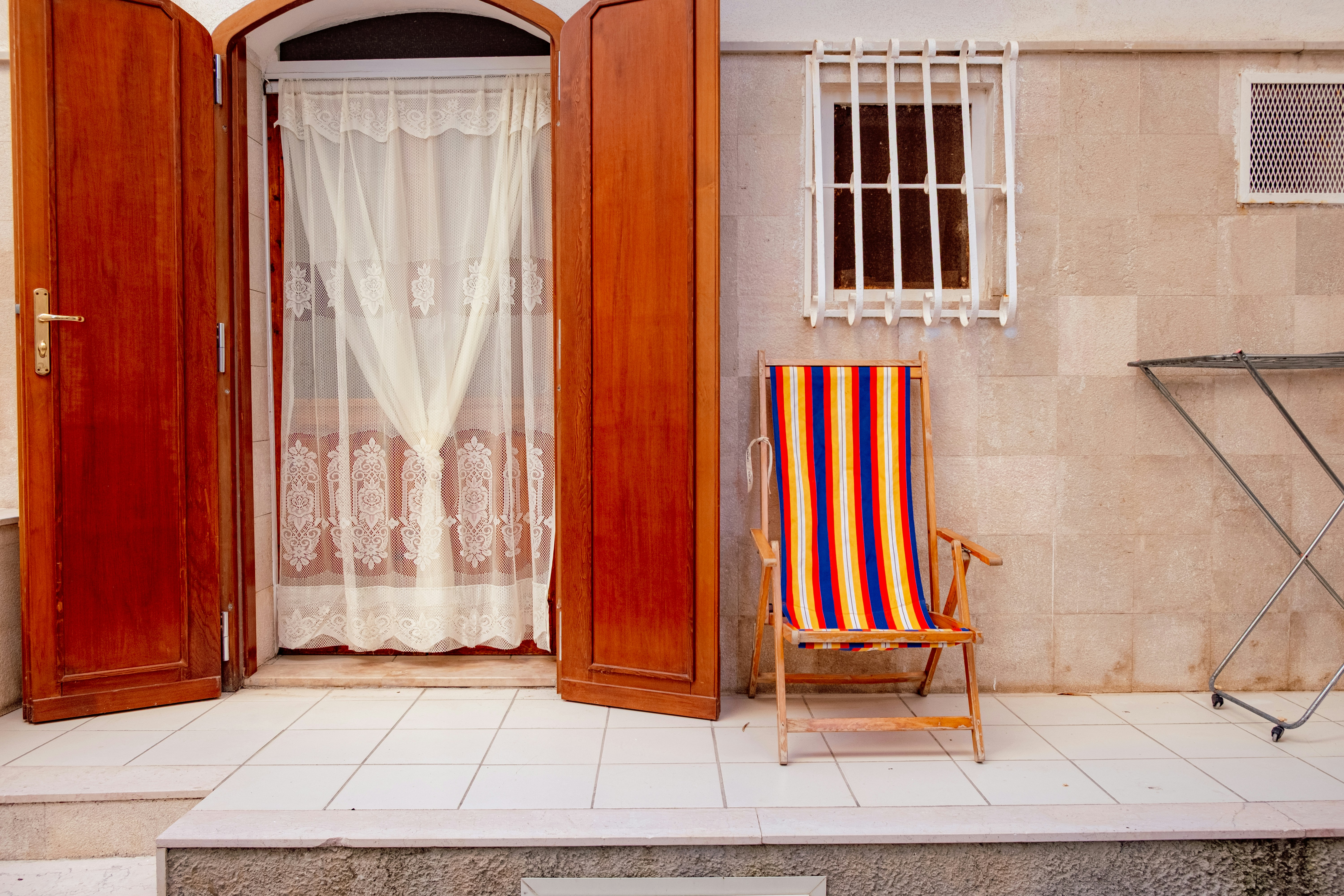  striped deck chair on a sunlit patio beside an open wooden doorway