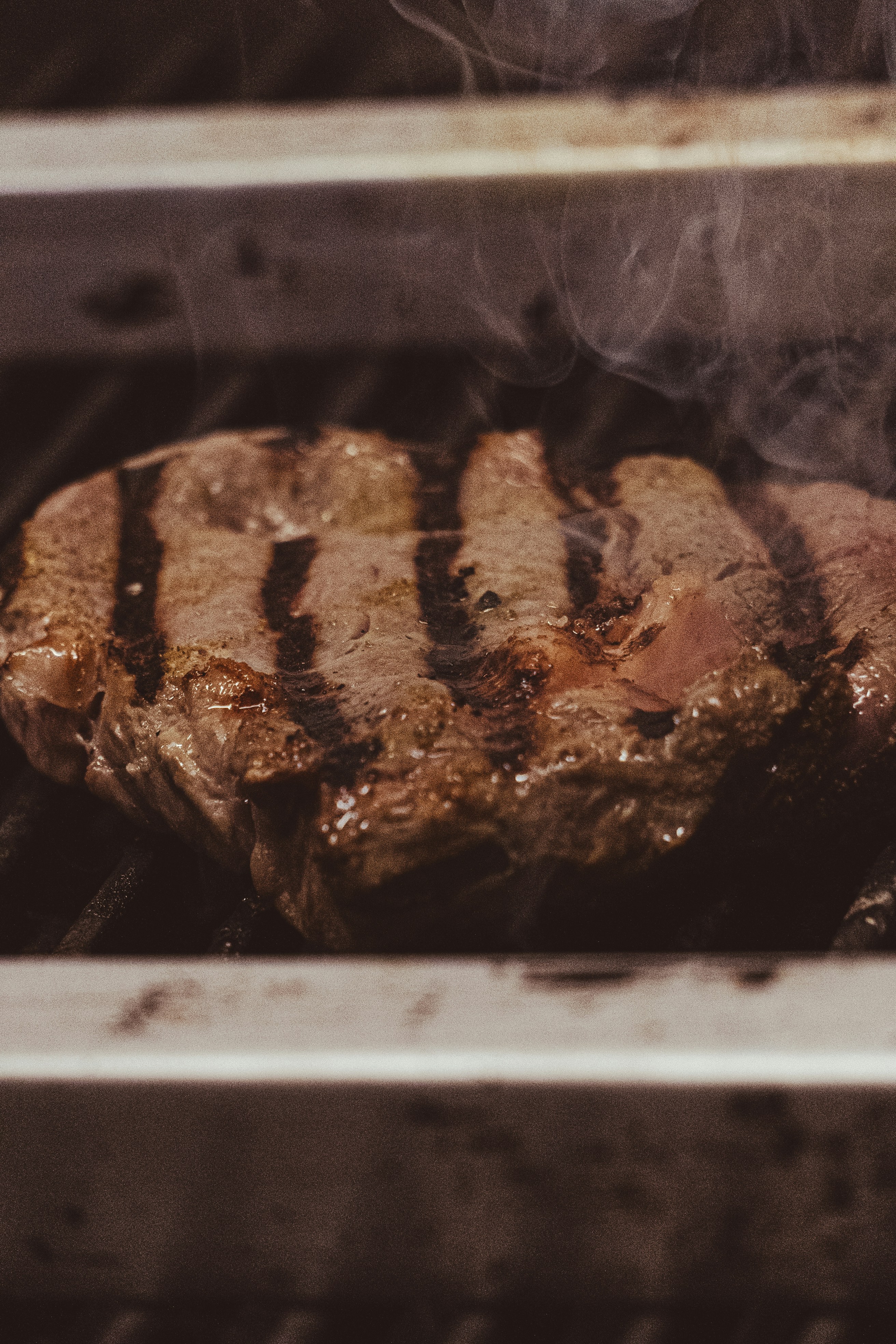 Charred Crests: A Close-Up of Grilled Steak on a Smoky Grill