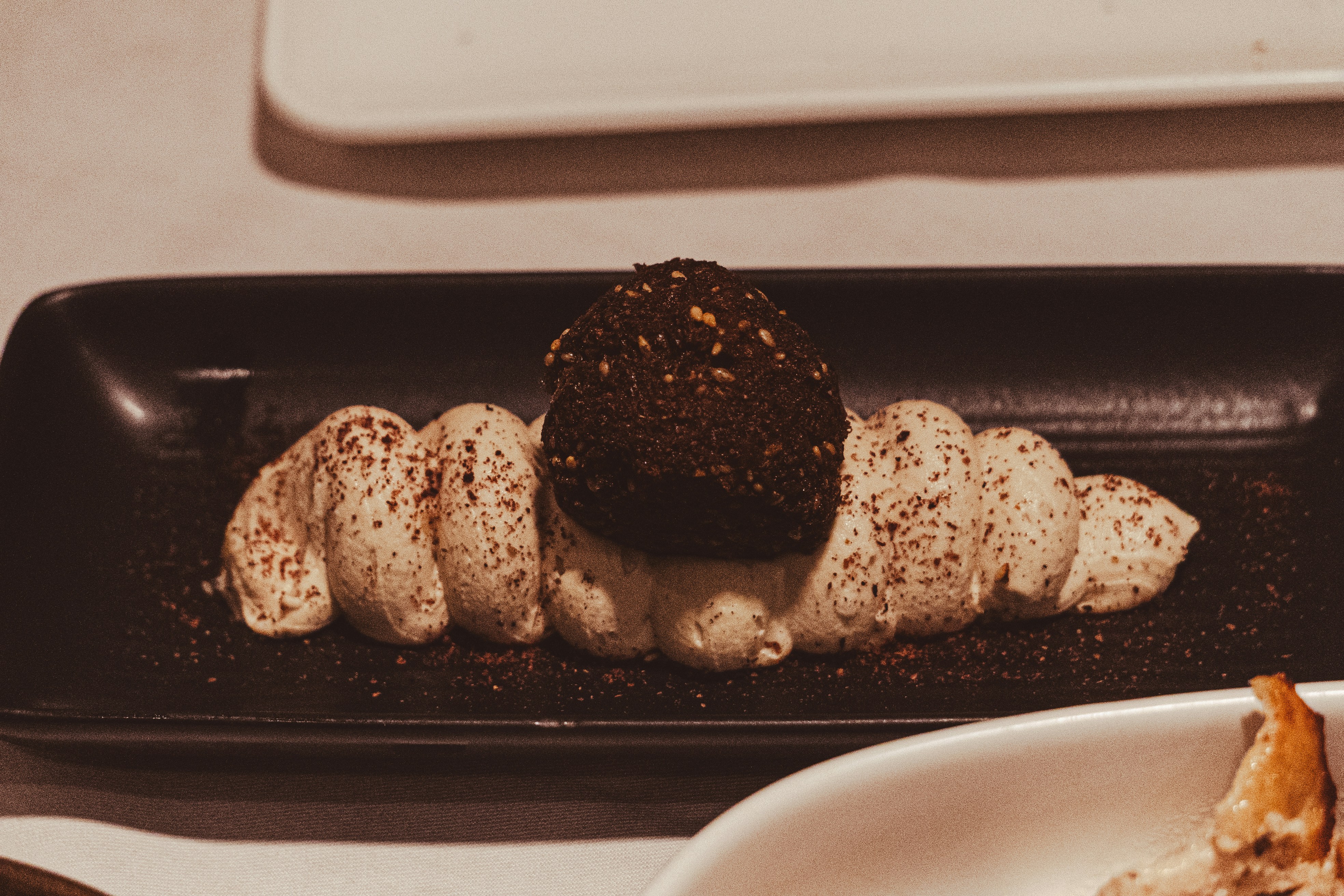 Chocolate-topped meringue quenelles on a sleek black plate