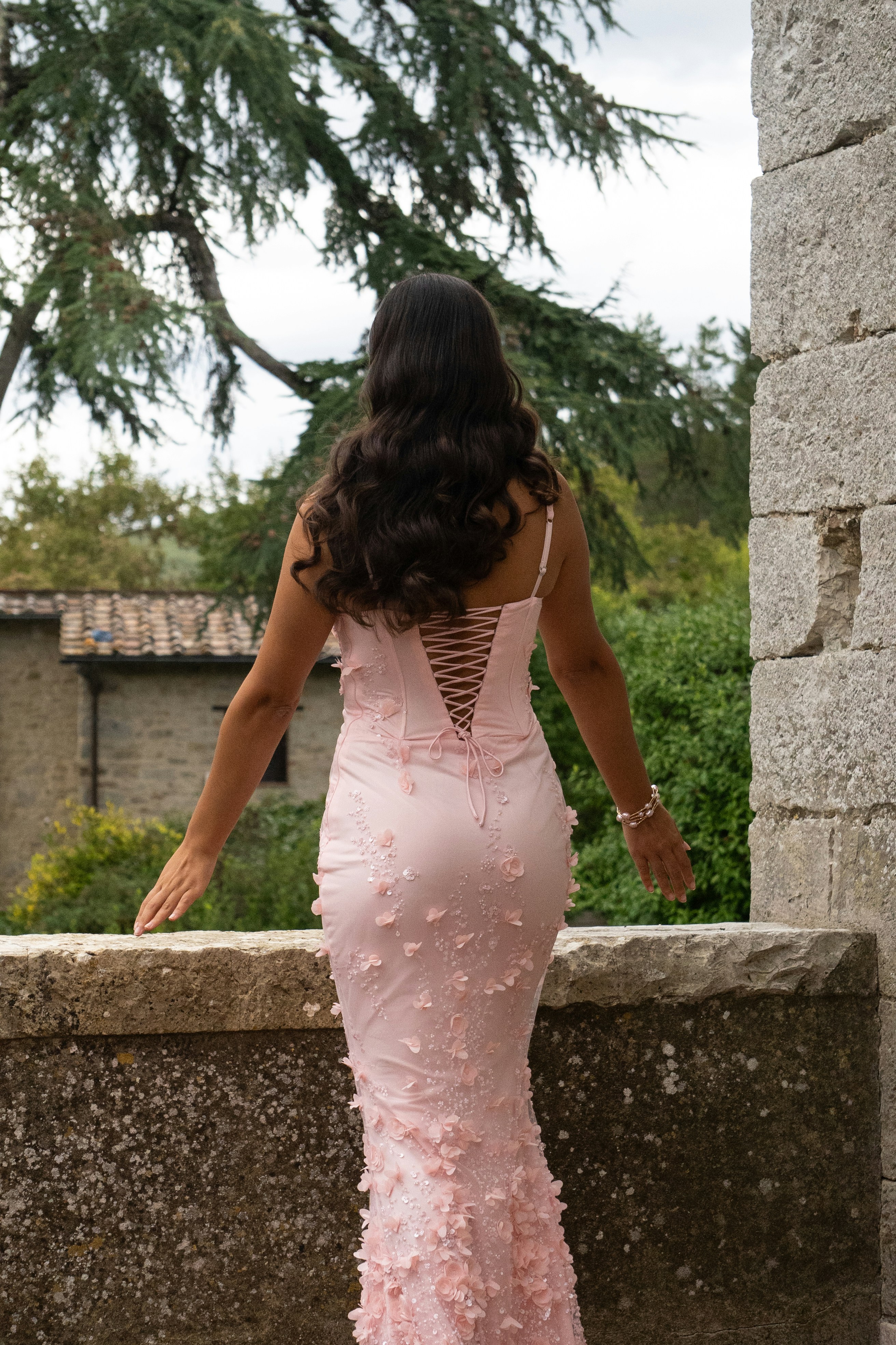 Pink lace-back gown stepping toward a stone terrace