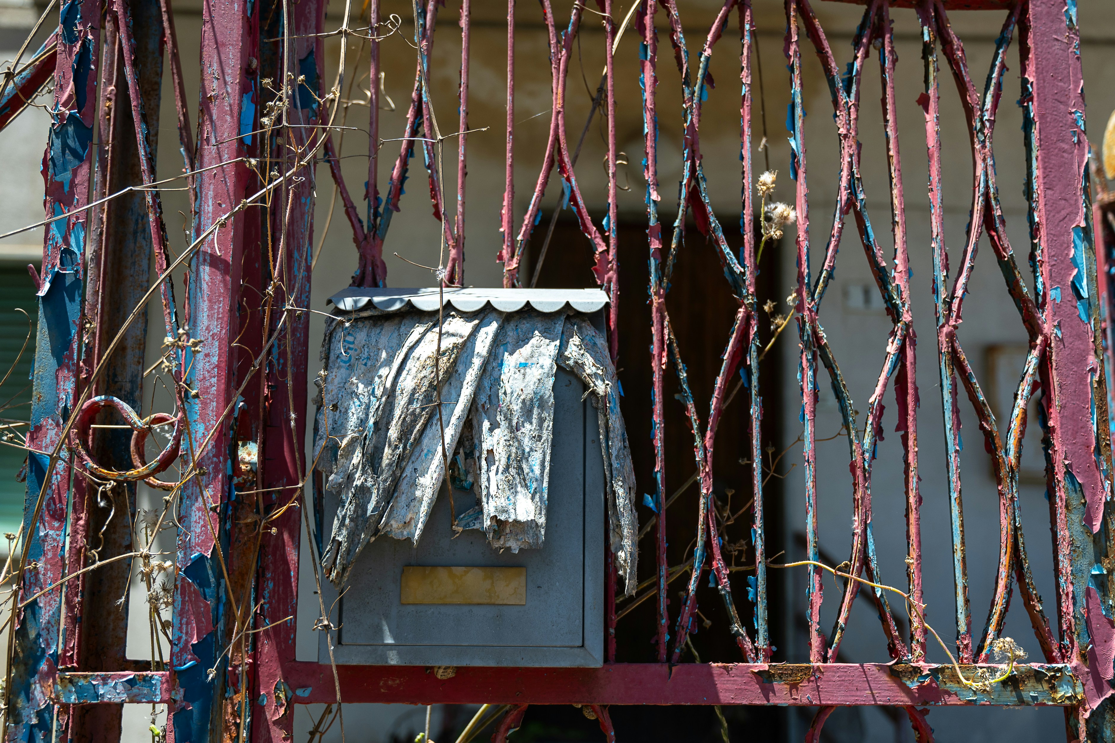 A Weathered Mailbox Nestled Behind Rusted Ironwork