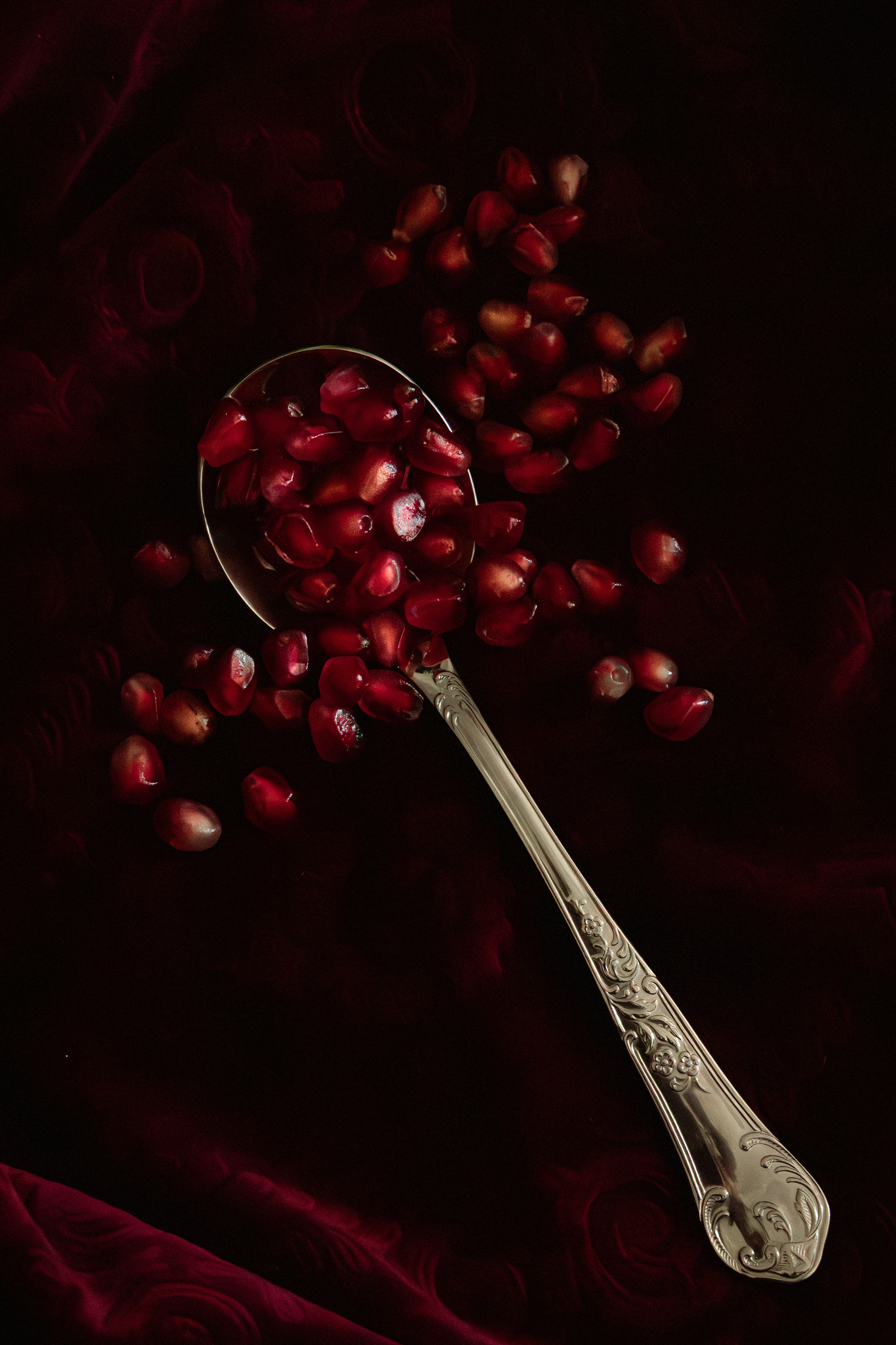 Crimson Harvest: Pomegranate Seeds Cascading from an Ornate Spoon